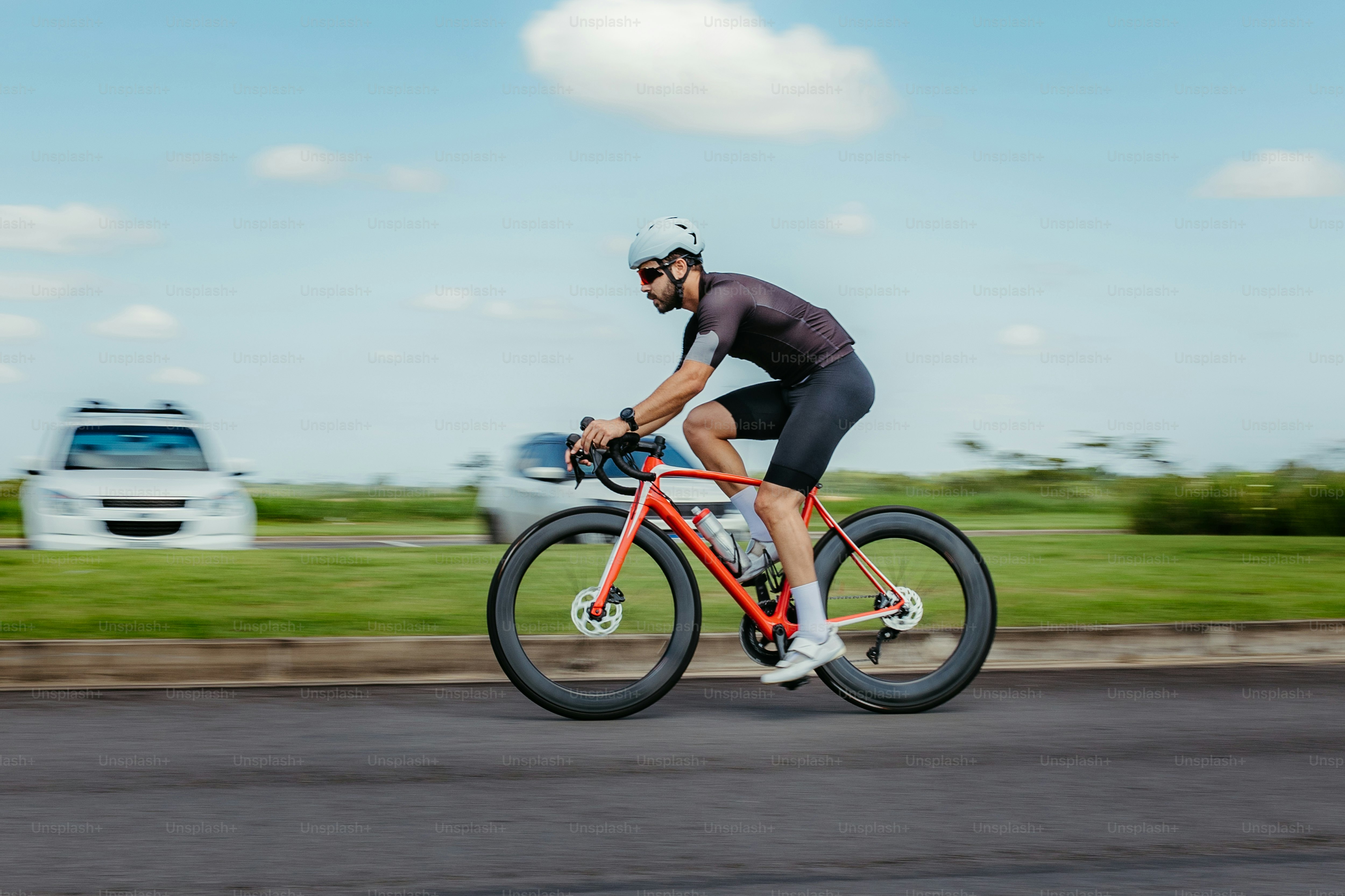 A man riding a red bike down a street photo – Bicycle Image on Unsplash