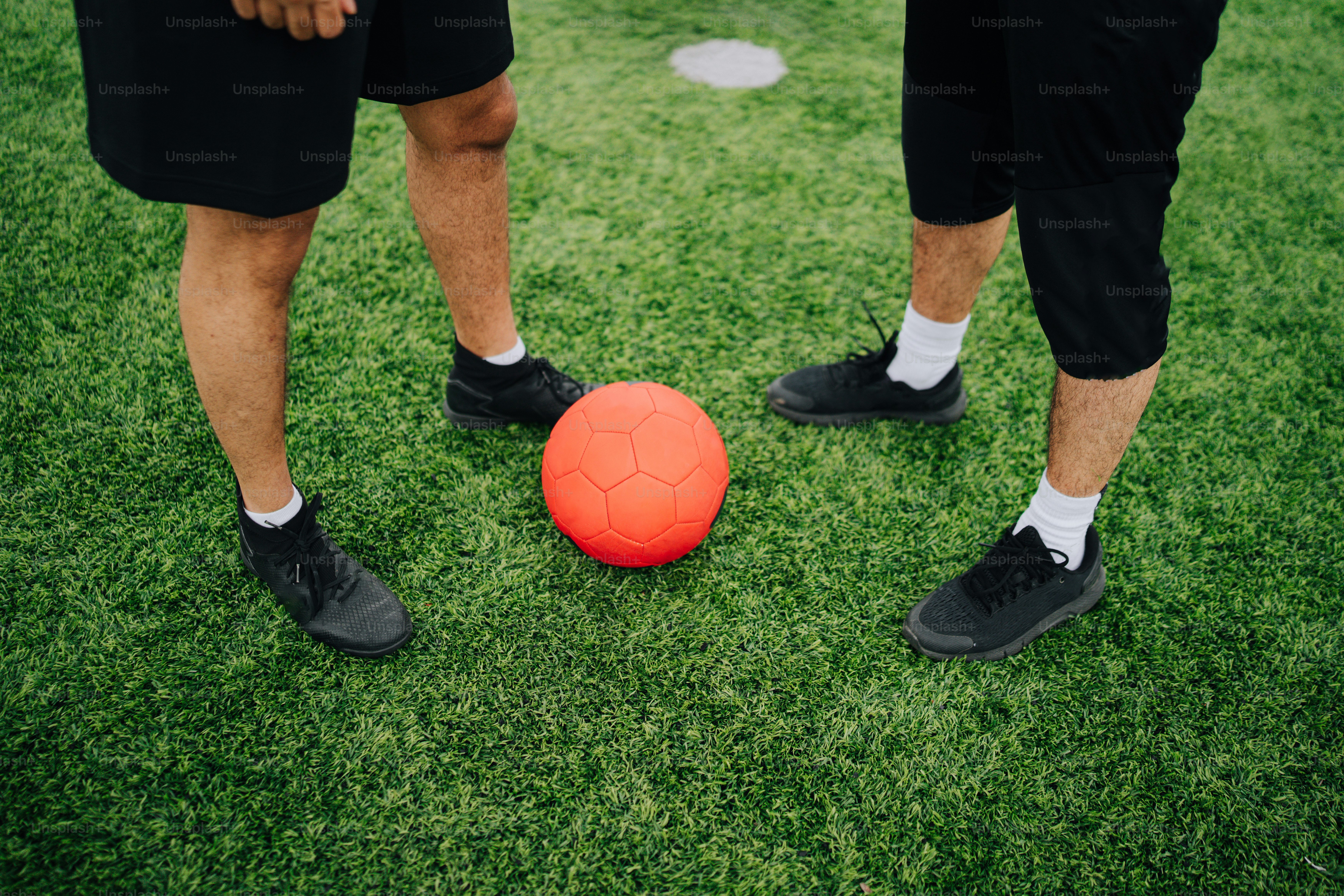 Two soccer players standing next to a ball on a field photo ...
