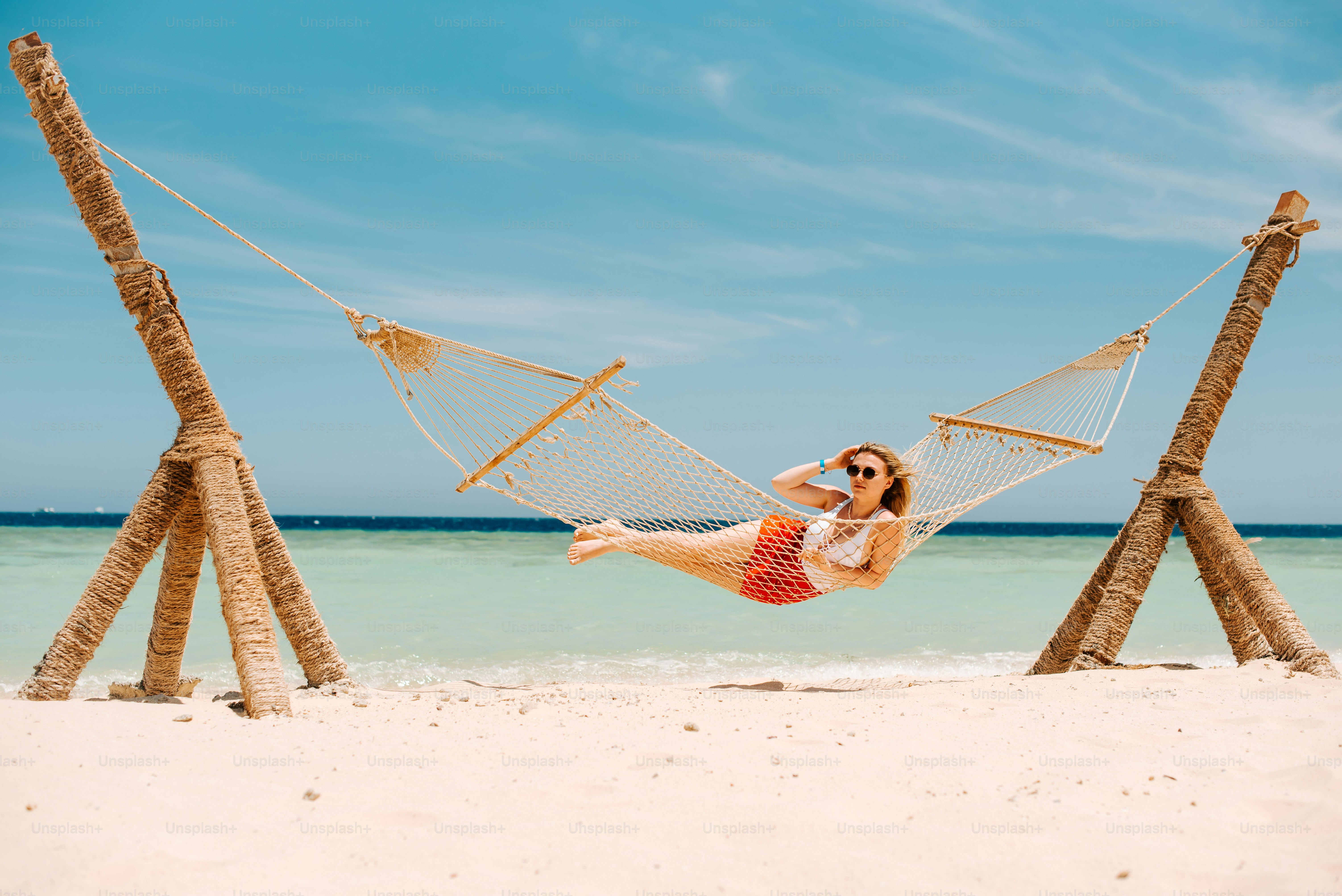 A woman laying in a hammock on the beach photo – Relax Image on Unsplash