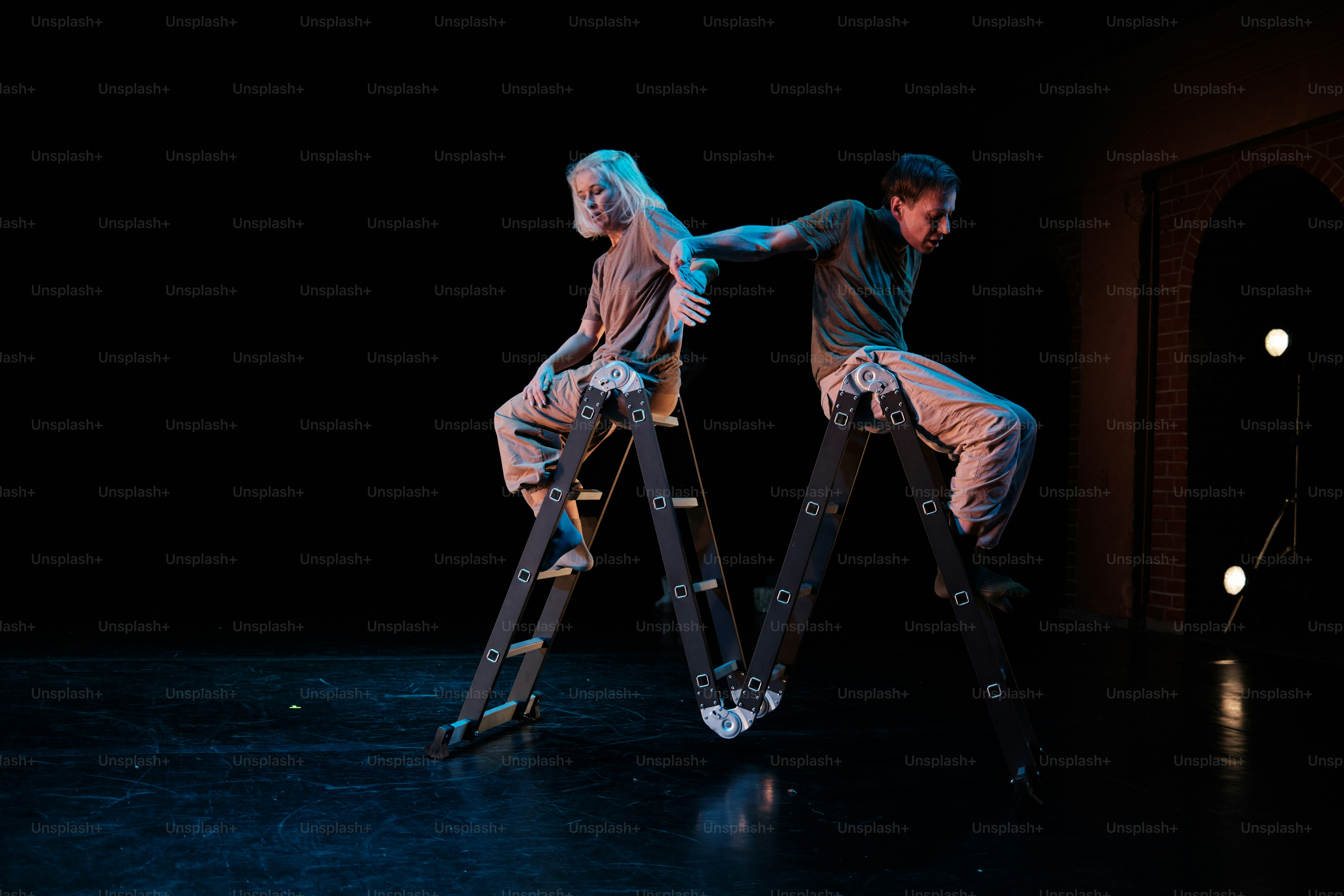 A couple of people that are sitting on some ladders photo – Theater ...