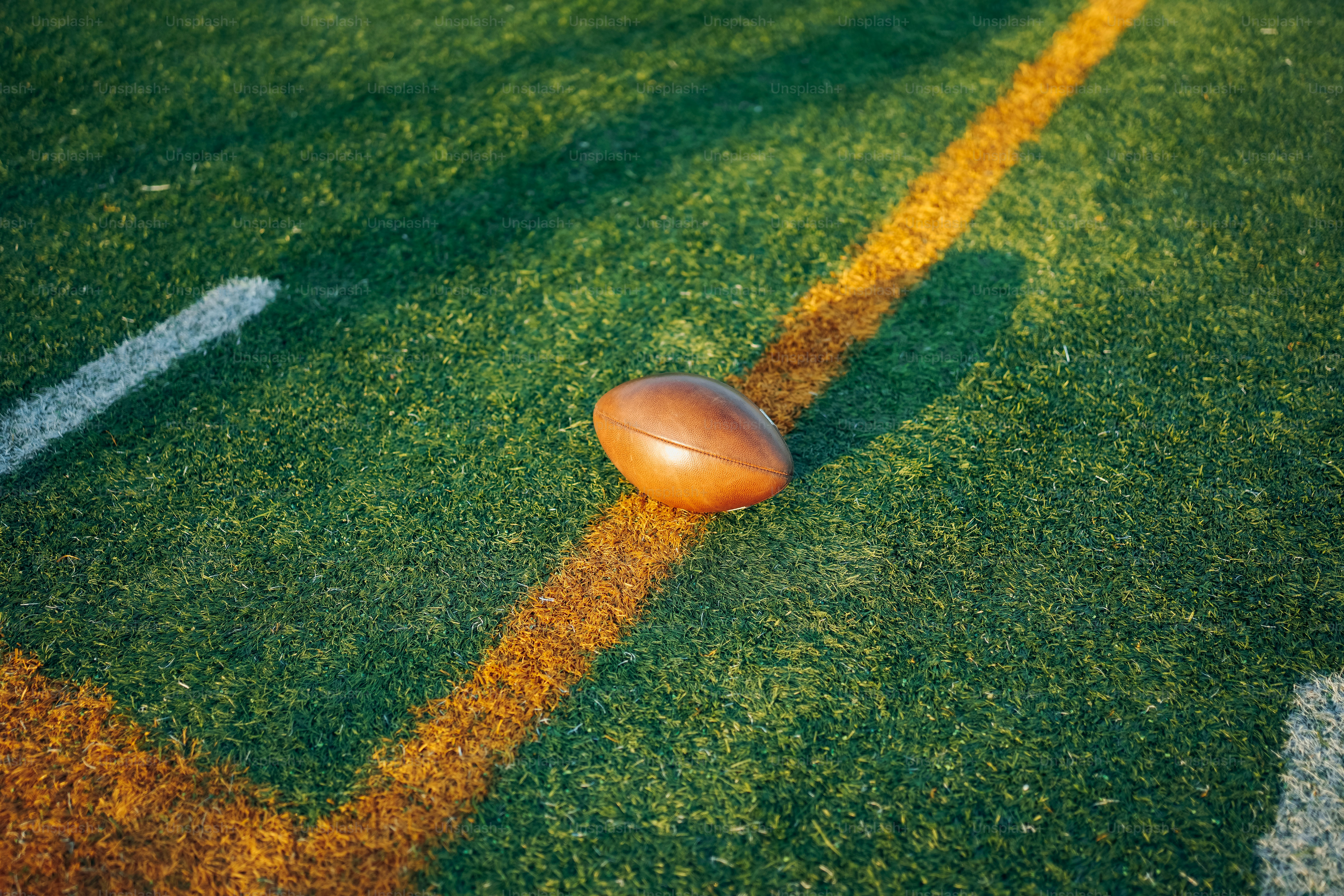 A football sitting on the side of a field photo – American football ...