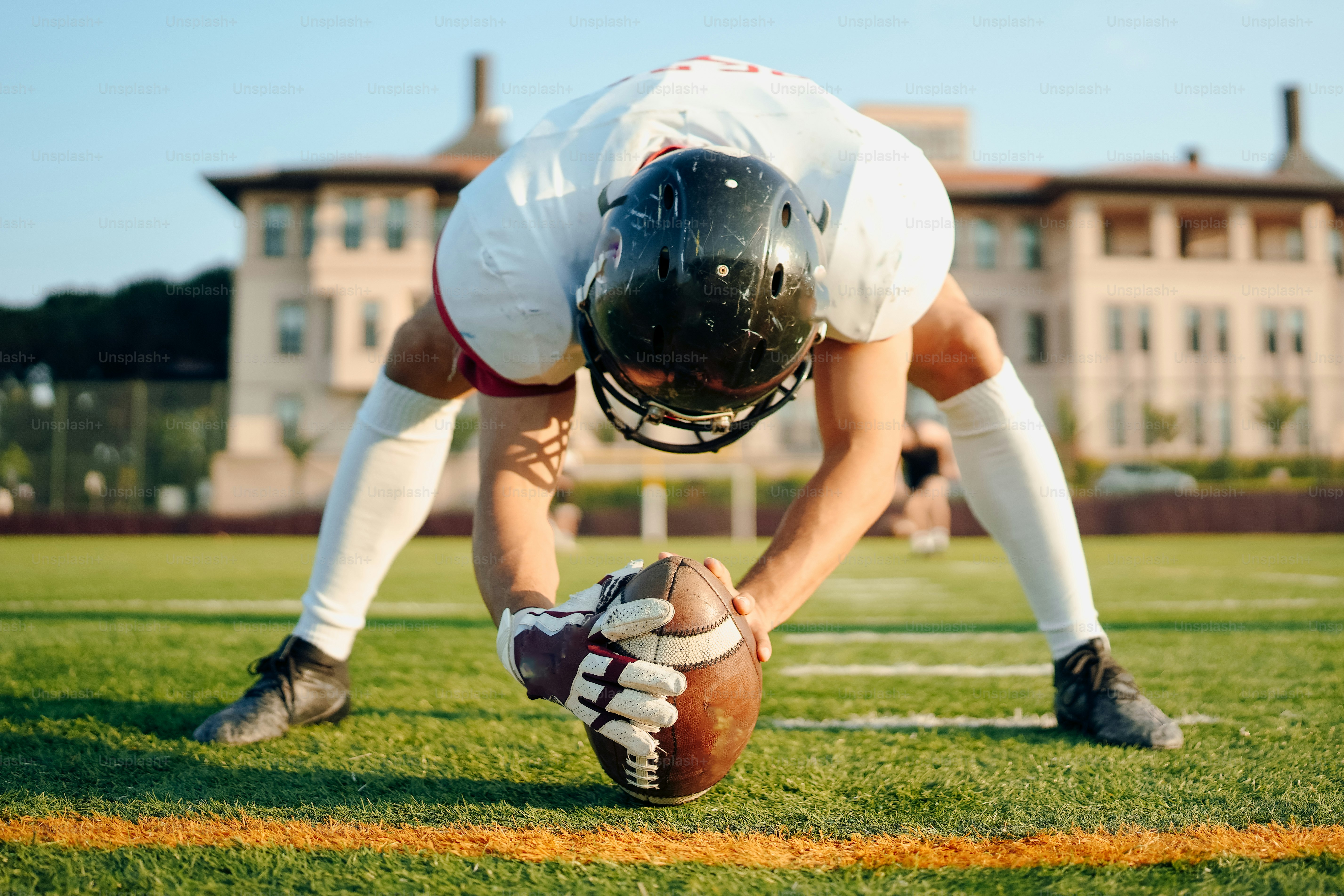 A football player bending over to pick up a ball photo – Sport Image on ...