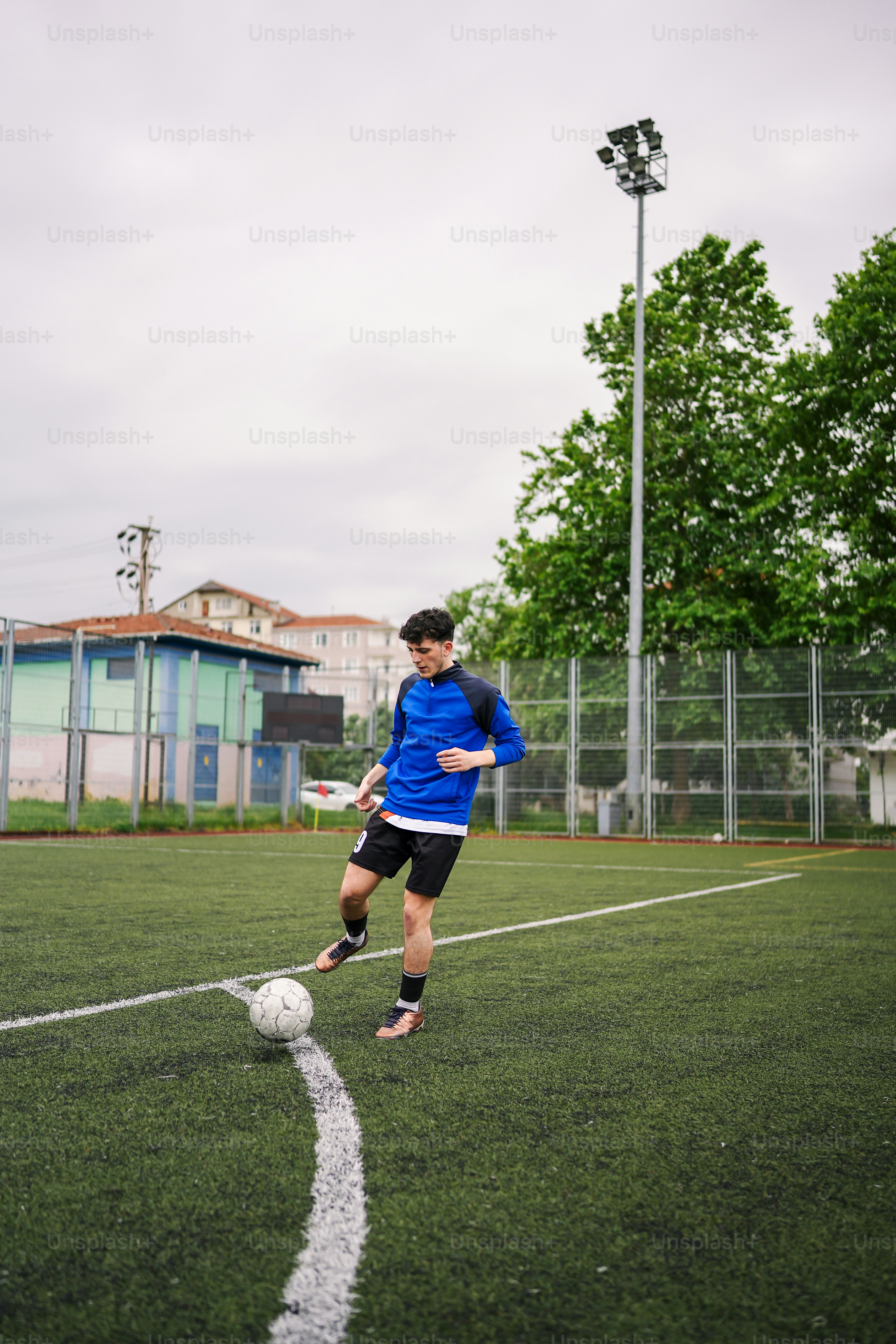 A young man kicking a soccer ball on a field photo – Football Image on ...