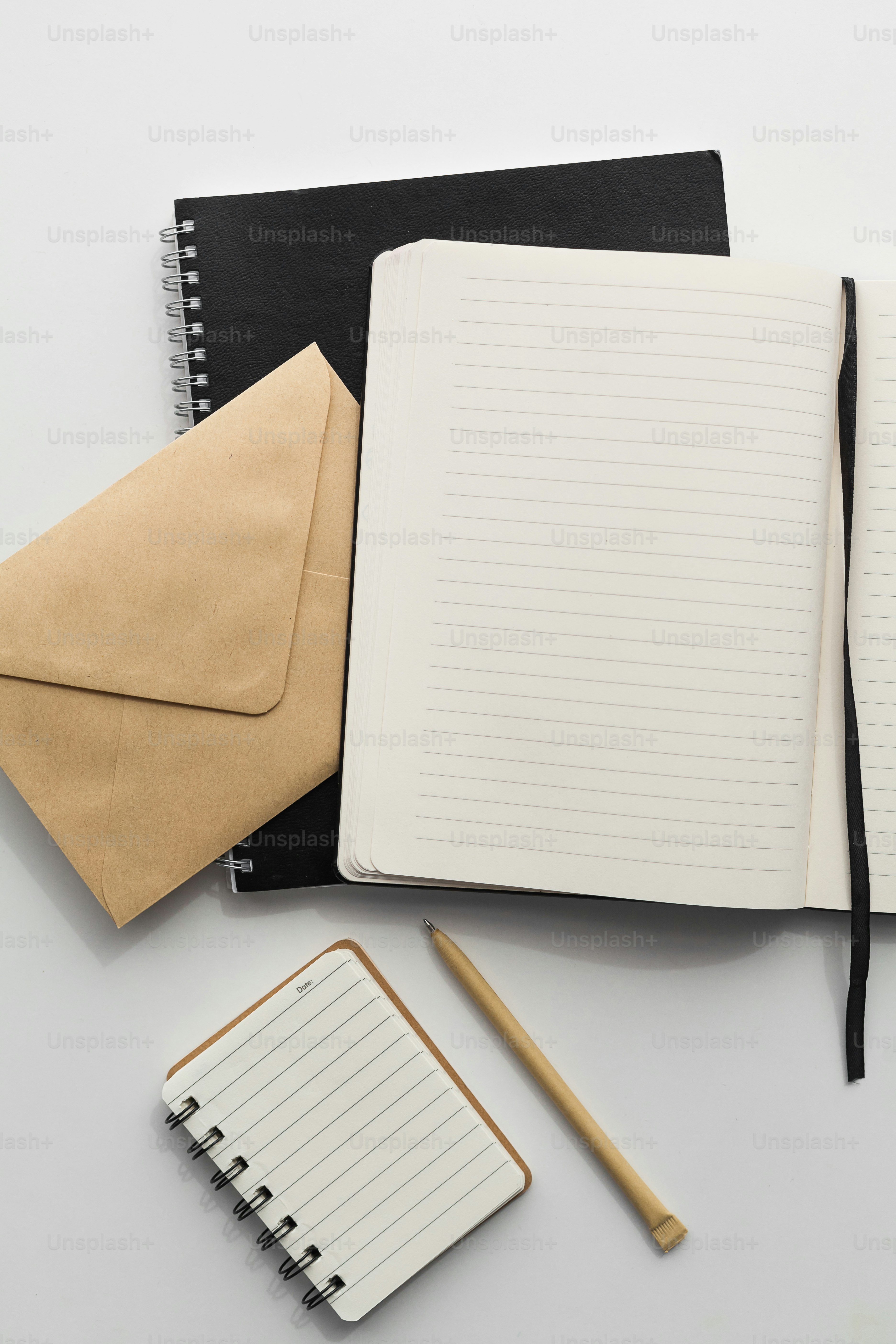 A notepad, pen, notebook, and envelope on a table photo – Desk Image on ...