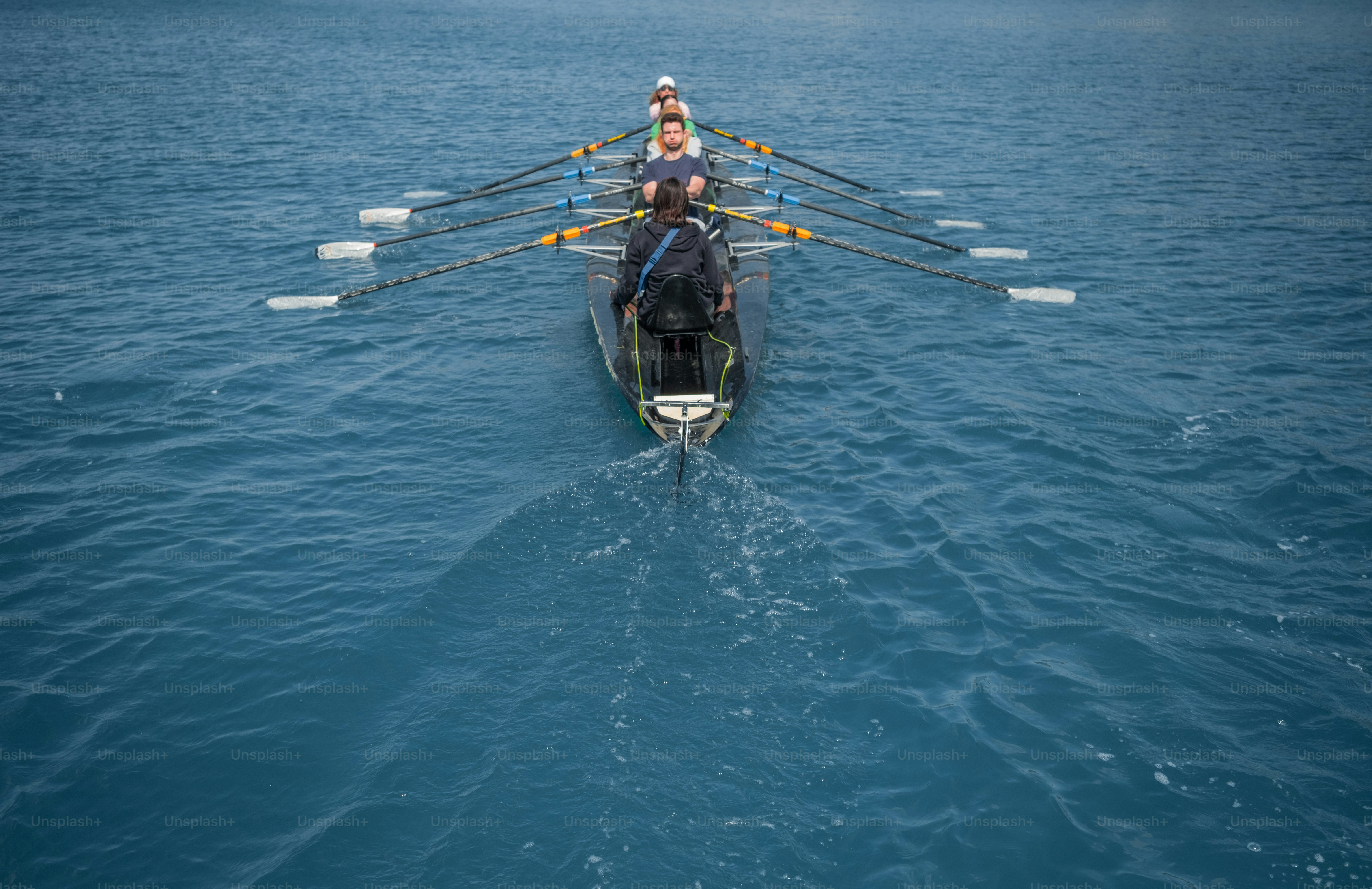 A woman rowing a boat in the middle of the ocean photo – Group activity ...