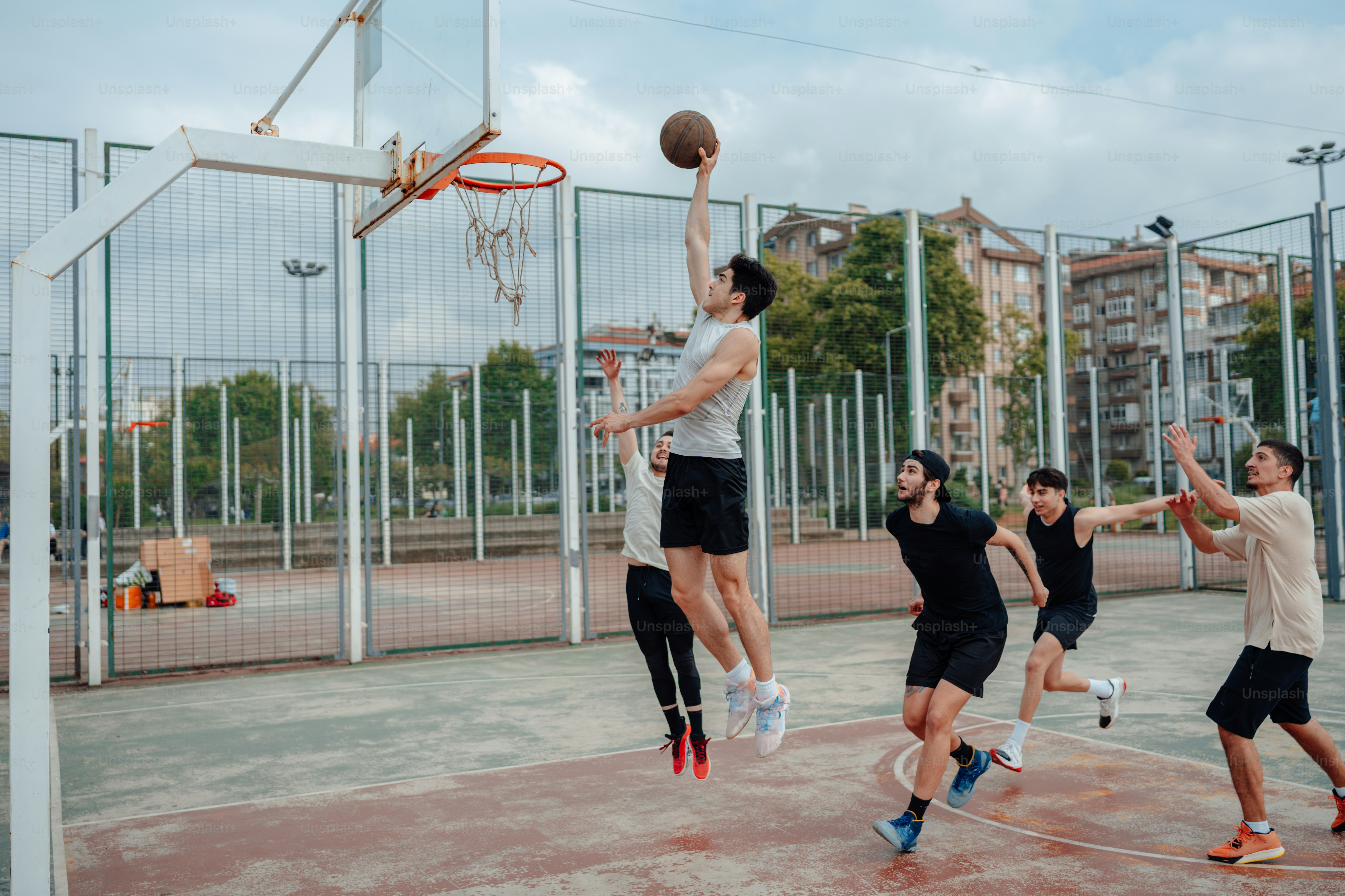 A group of young men playing a game of basketball photo – Basketball ...