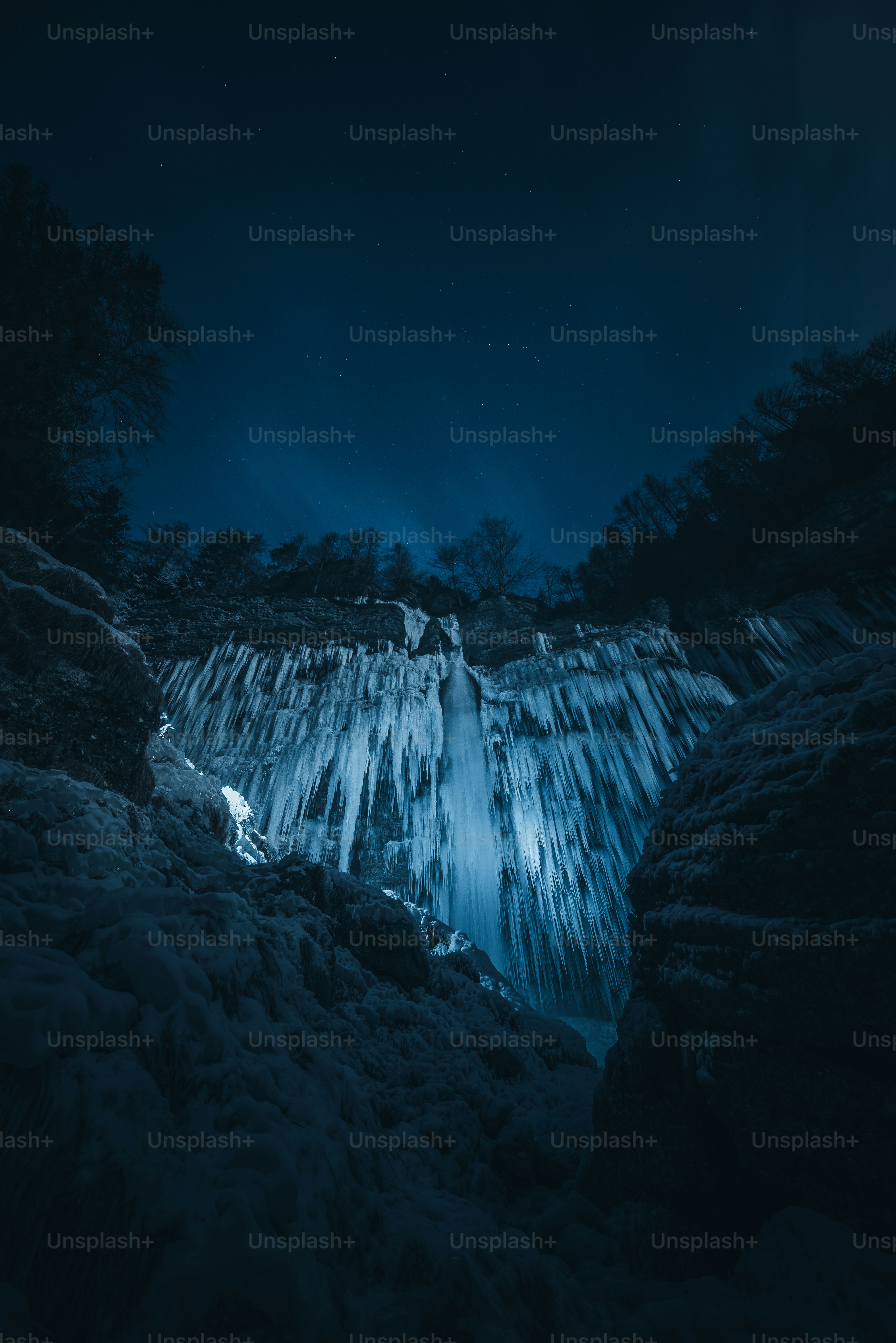 A frozen waterfall in the middle of a forest at night photo – Mobile ...