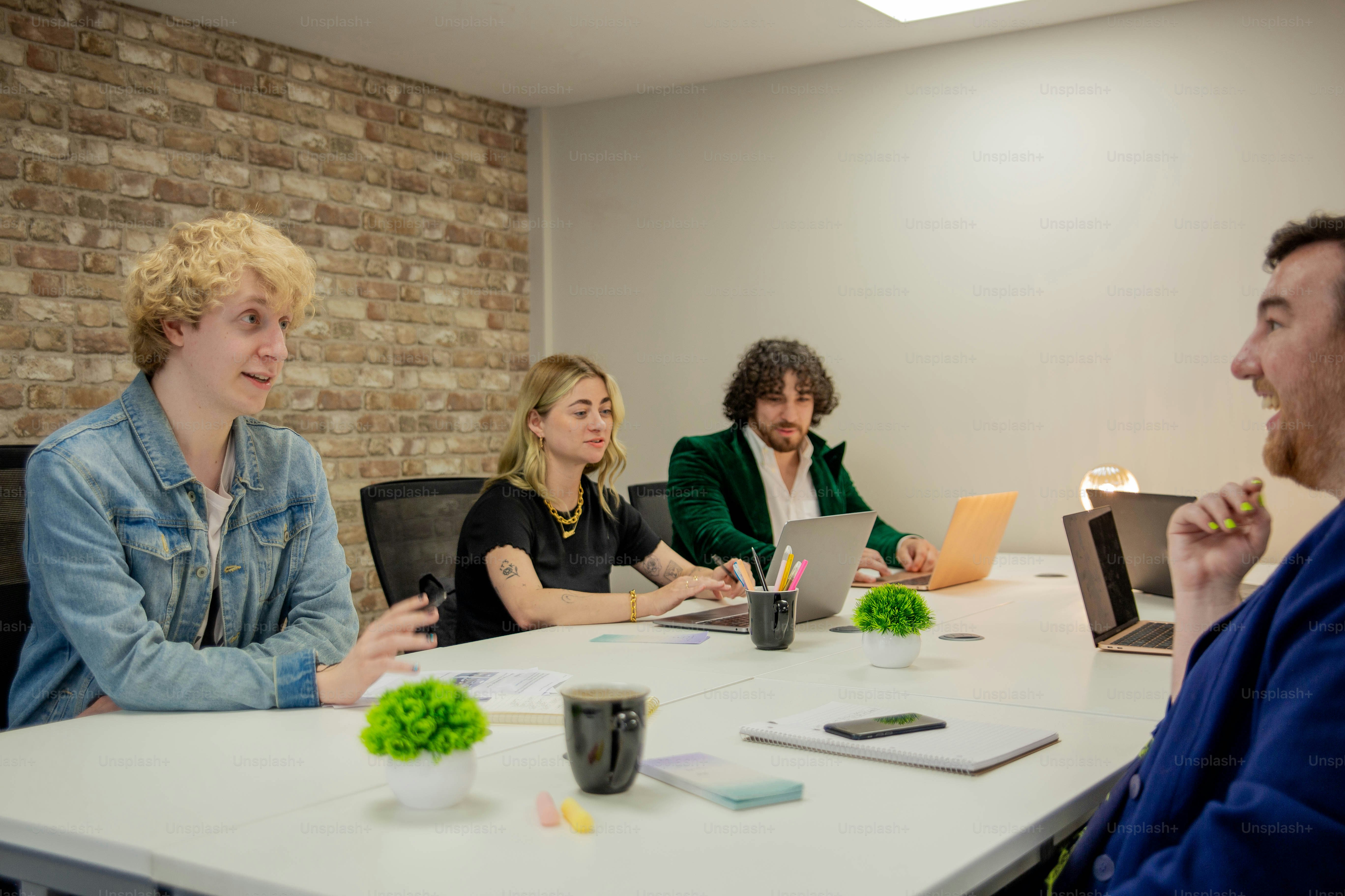 A group of people sitting around a table with laptops photo – Working ...