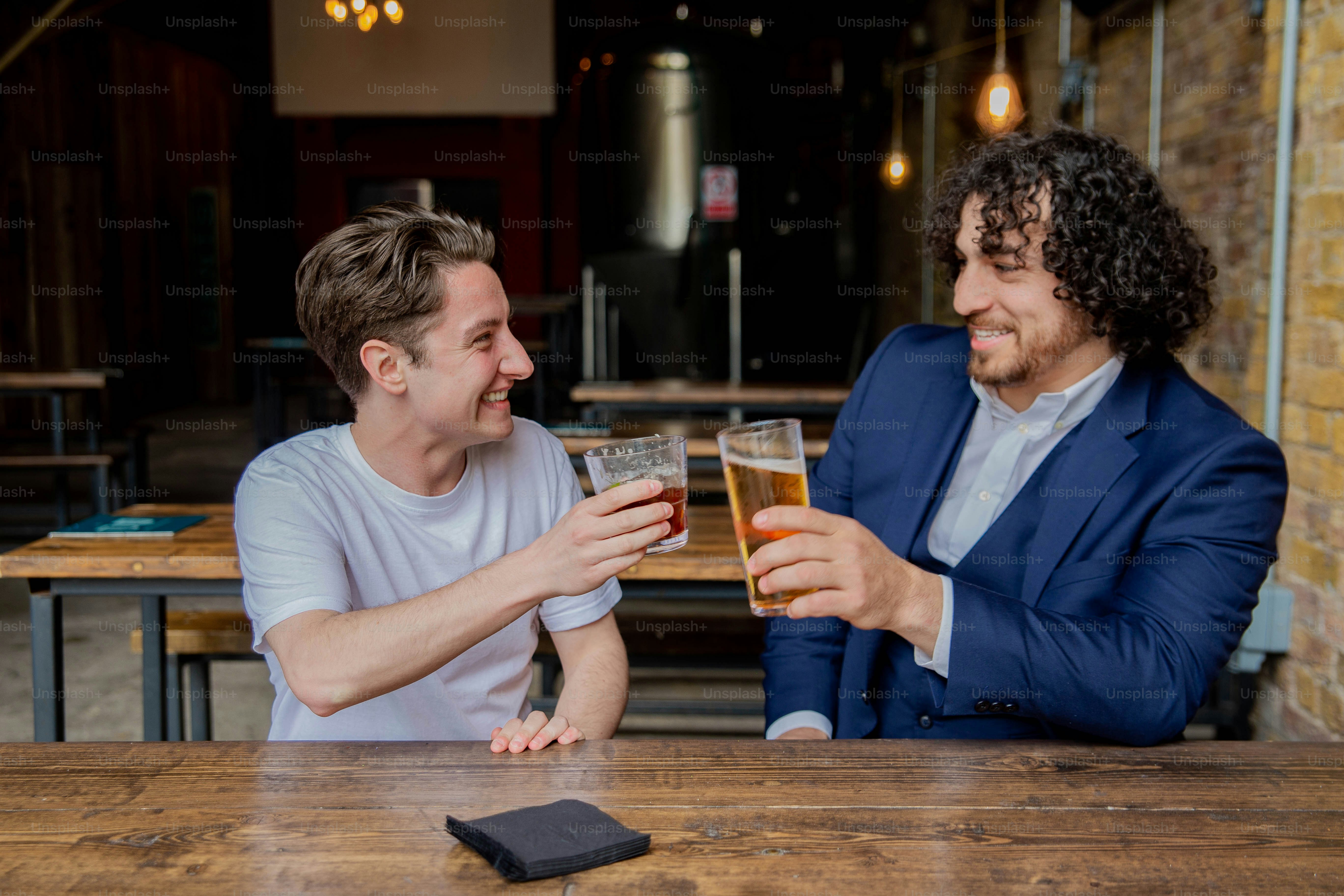 A couple of men sitting at a table with drinks photo – Work socialising ...