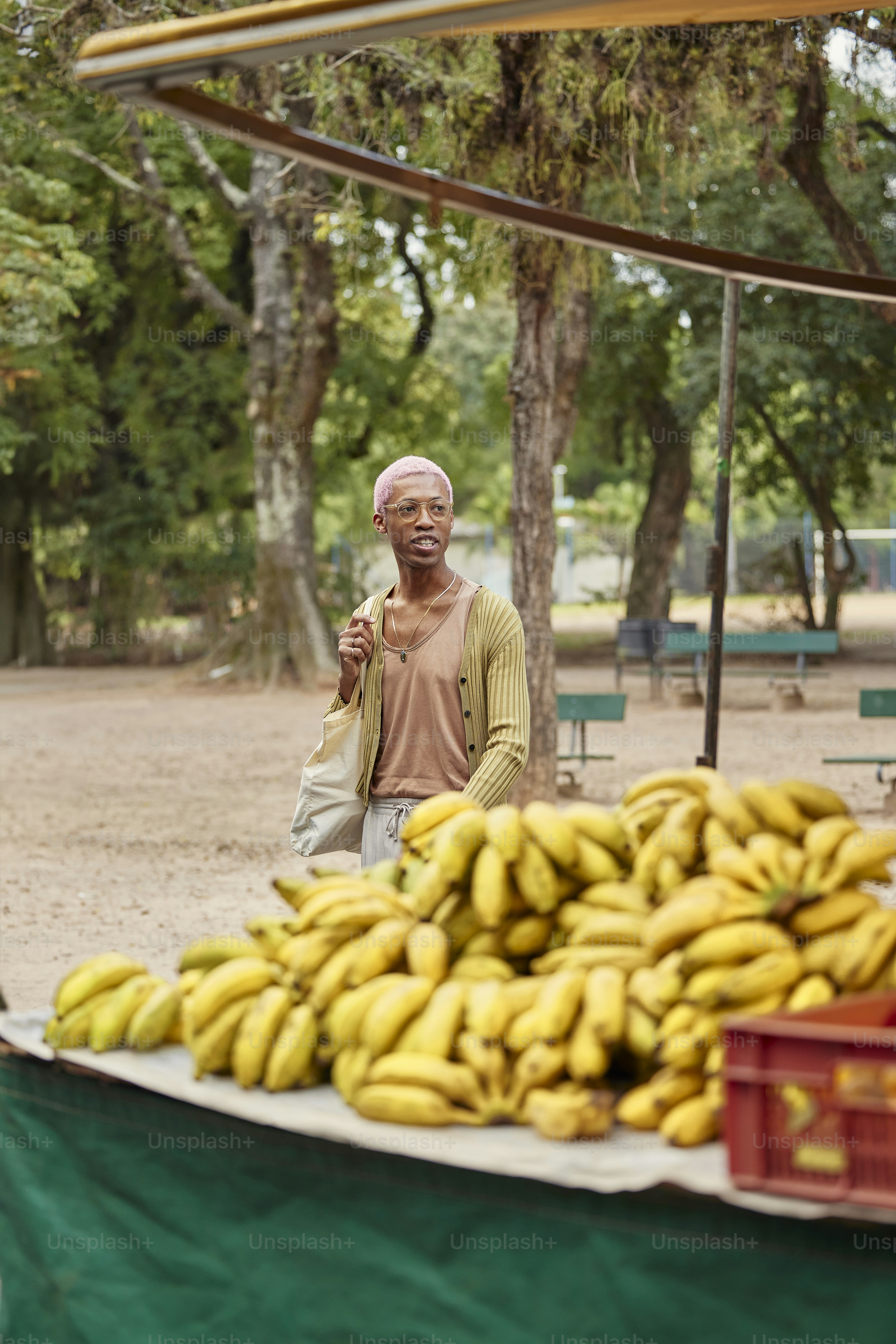 A man standing next to a pile of bananas photo – Farmers market Image ...