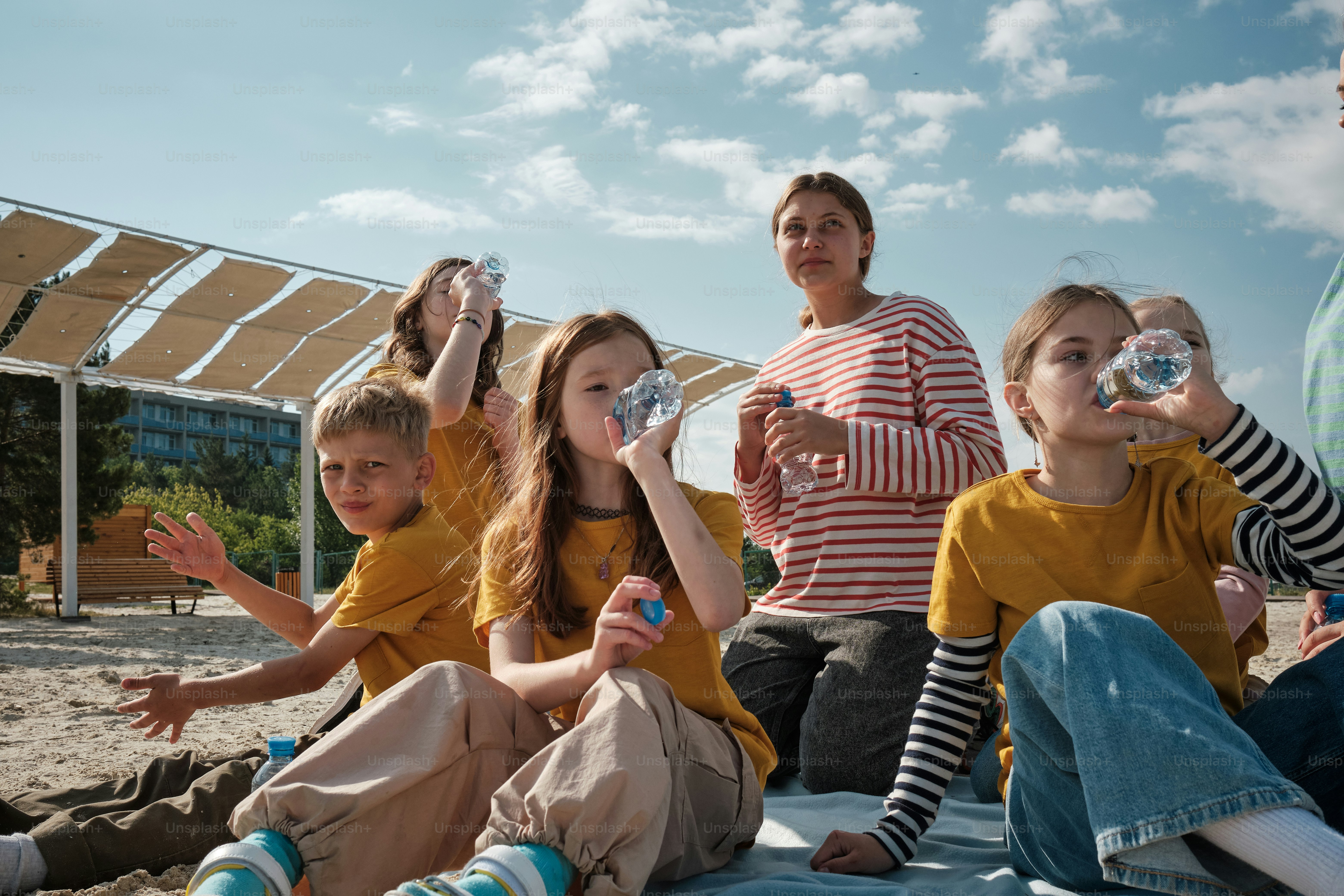 A group of children sitting on the ground drinking water photo ...