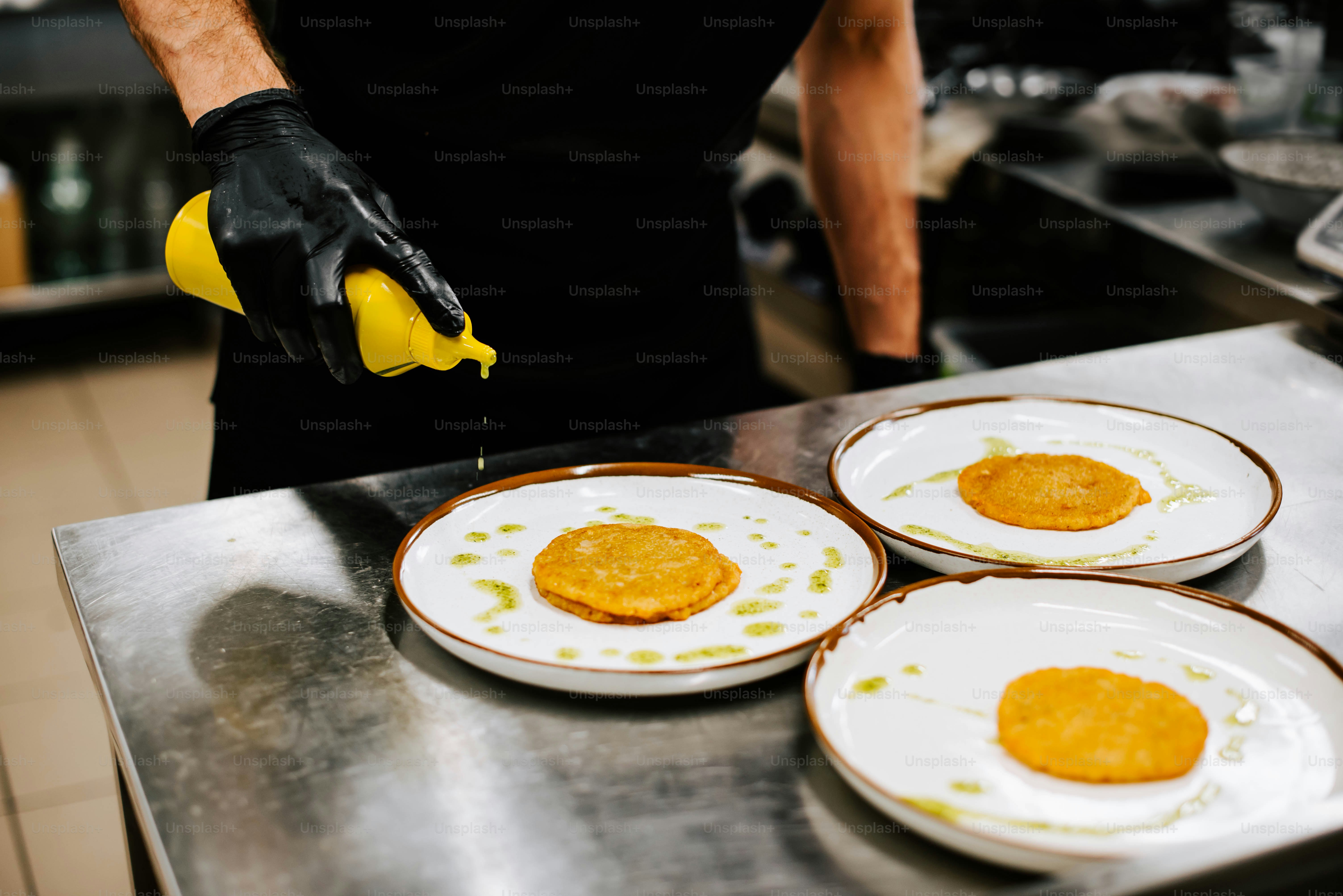 A person in a kitchen preparing food on plates photo – Food Image on ...