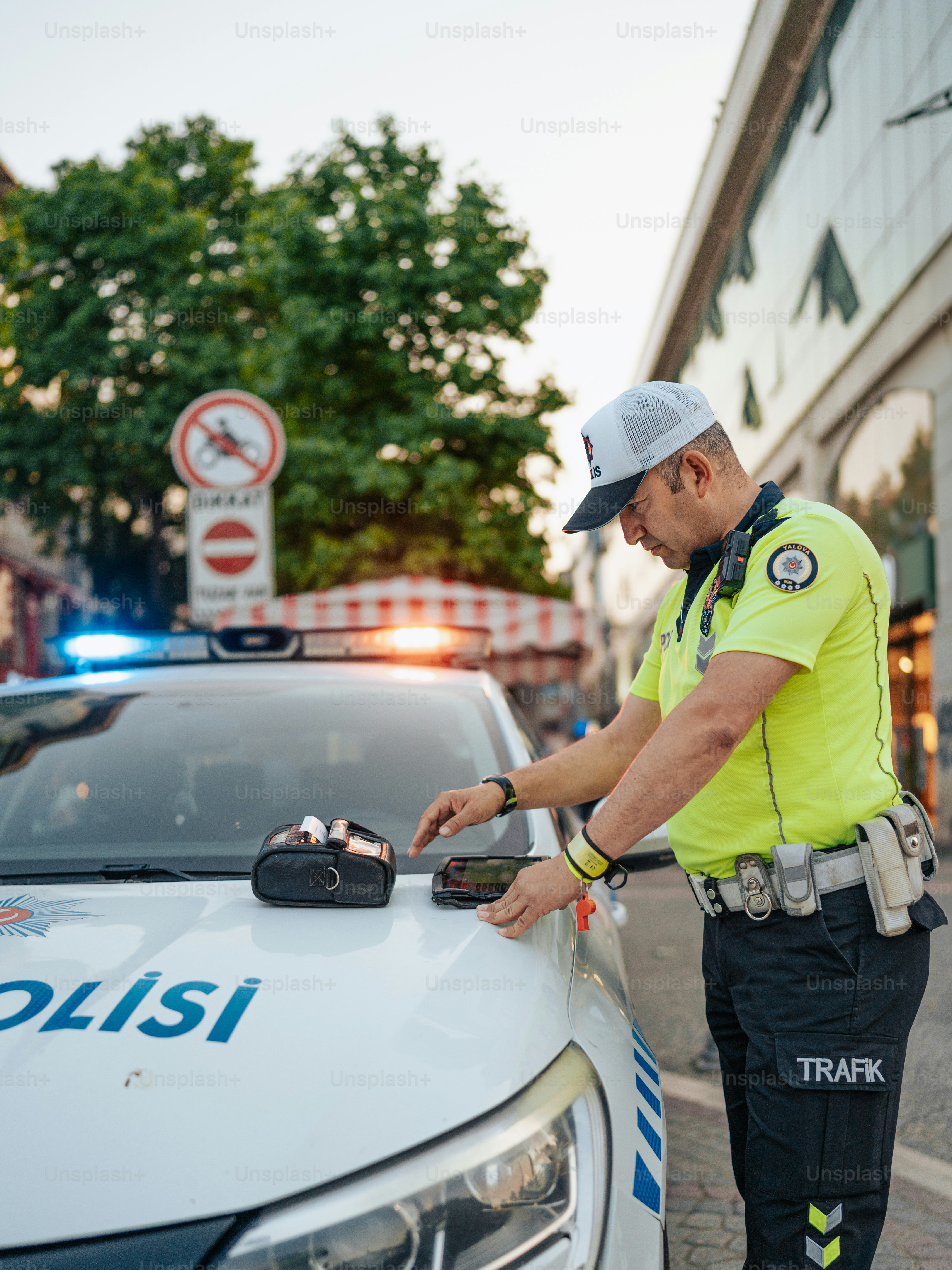 A police officer standing next to a police car photo – Police car Image ...