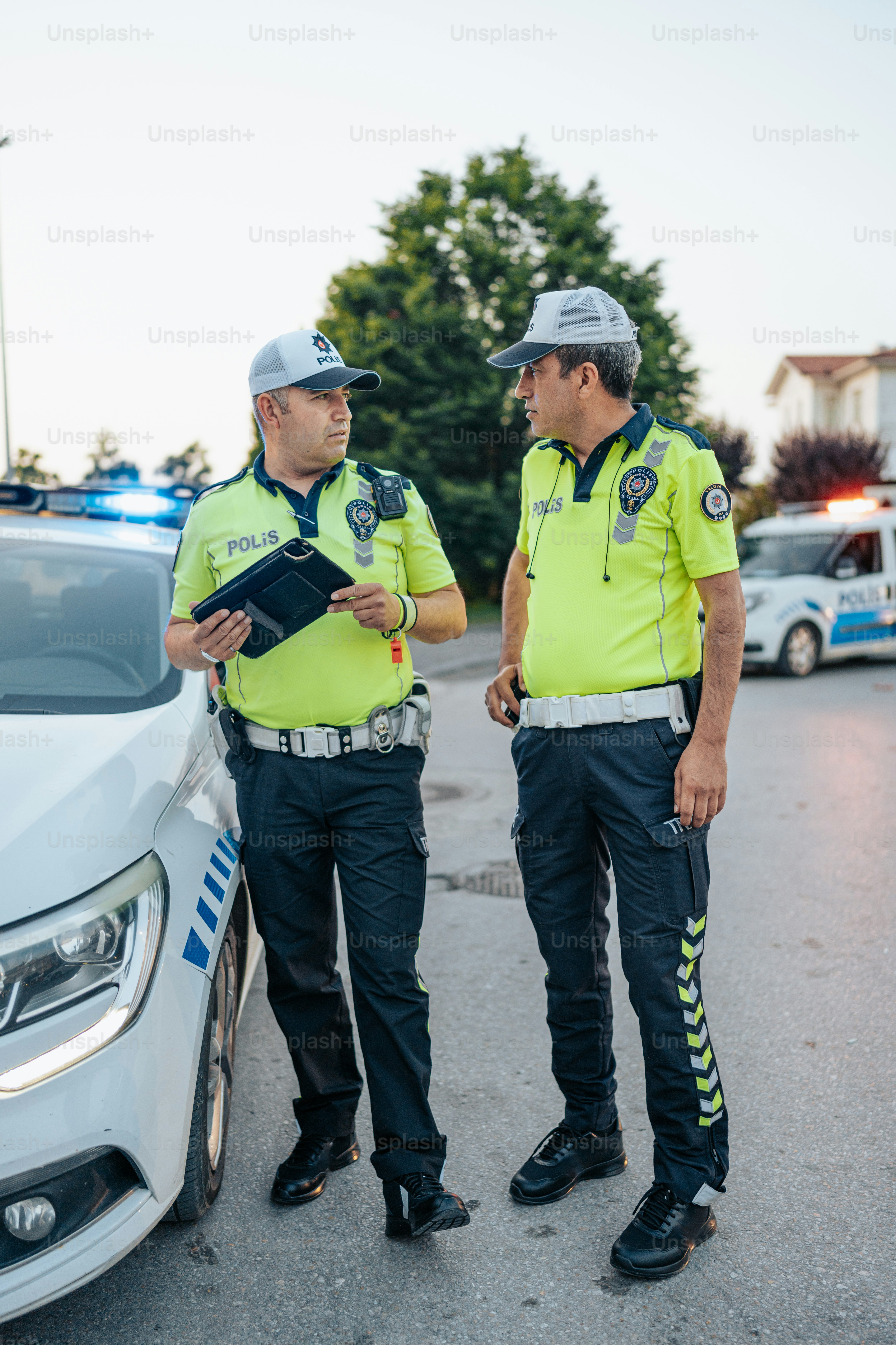 Two police officers standing next to each other photo – Police car ...