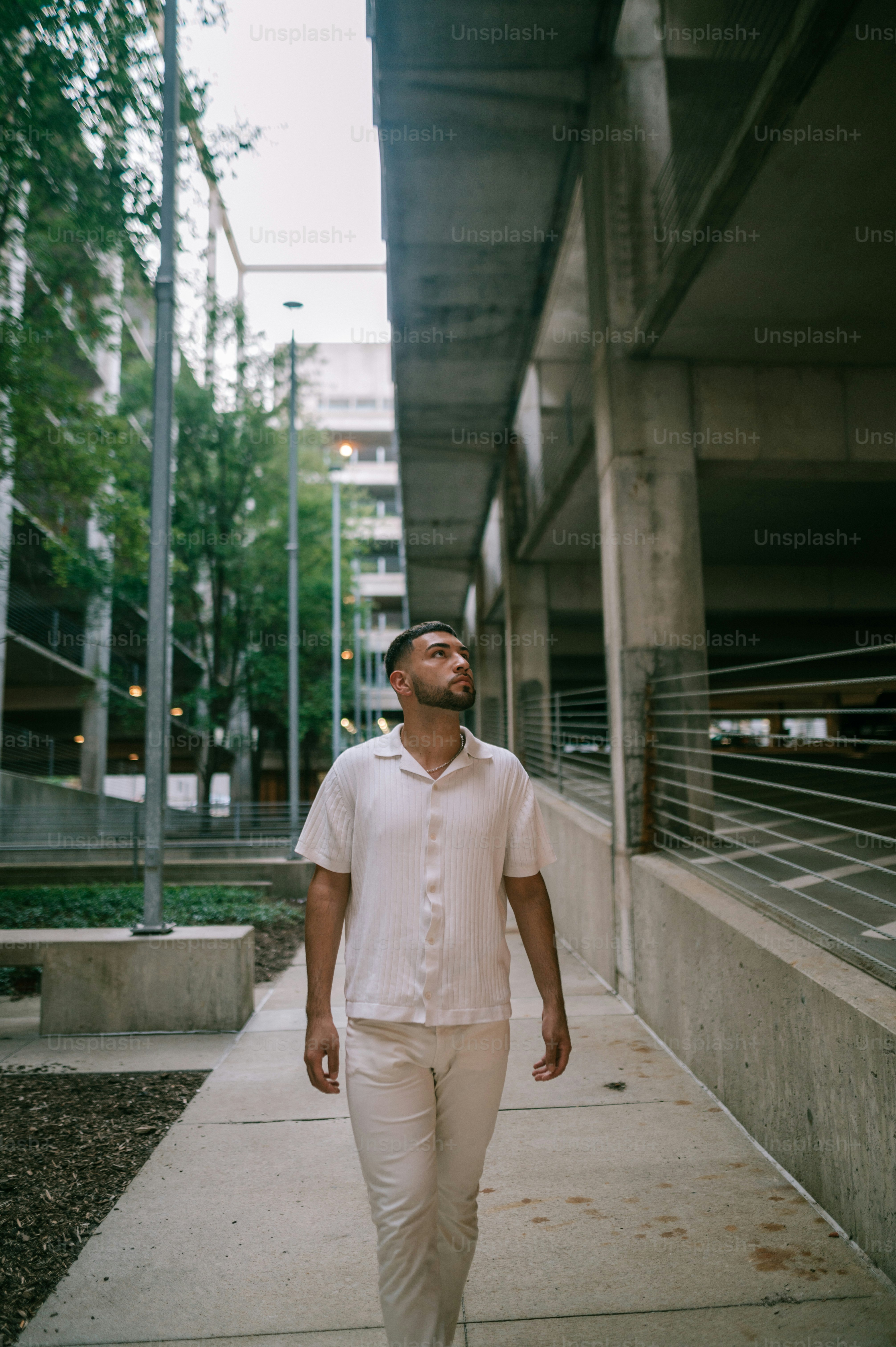 Un hombre caminando por una acera debajo de un puente foto – Imagen de ...