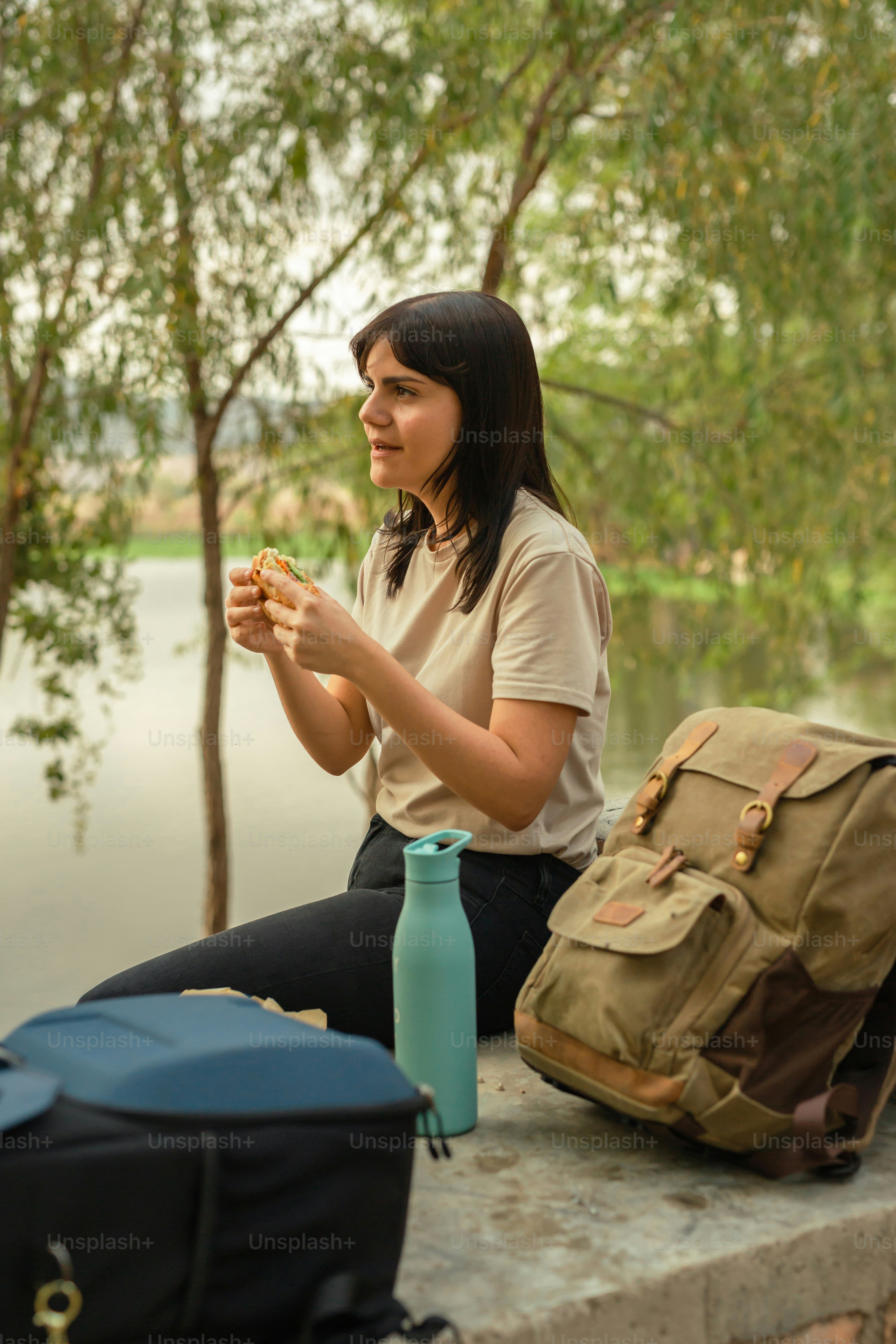 A woman sitting on a ledge eating food photo – Summer travel Image on ...