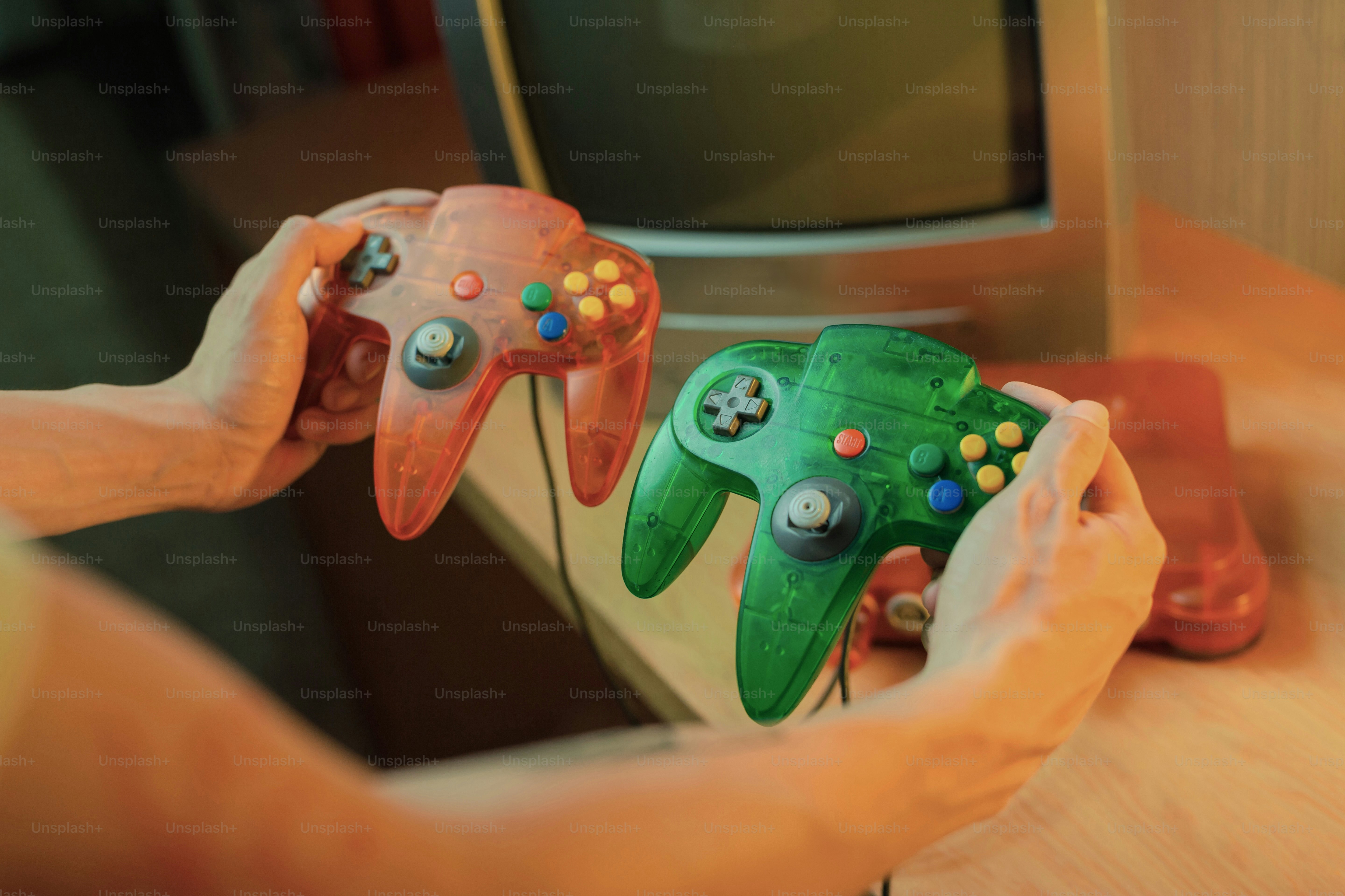 A person holding two video game controllers in front of a tv photo ...