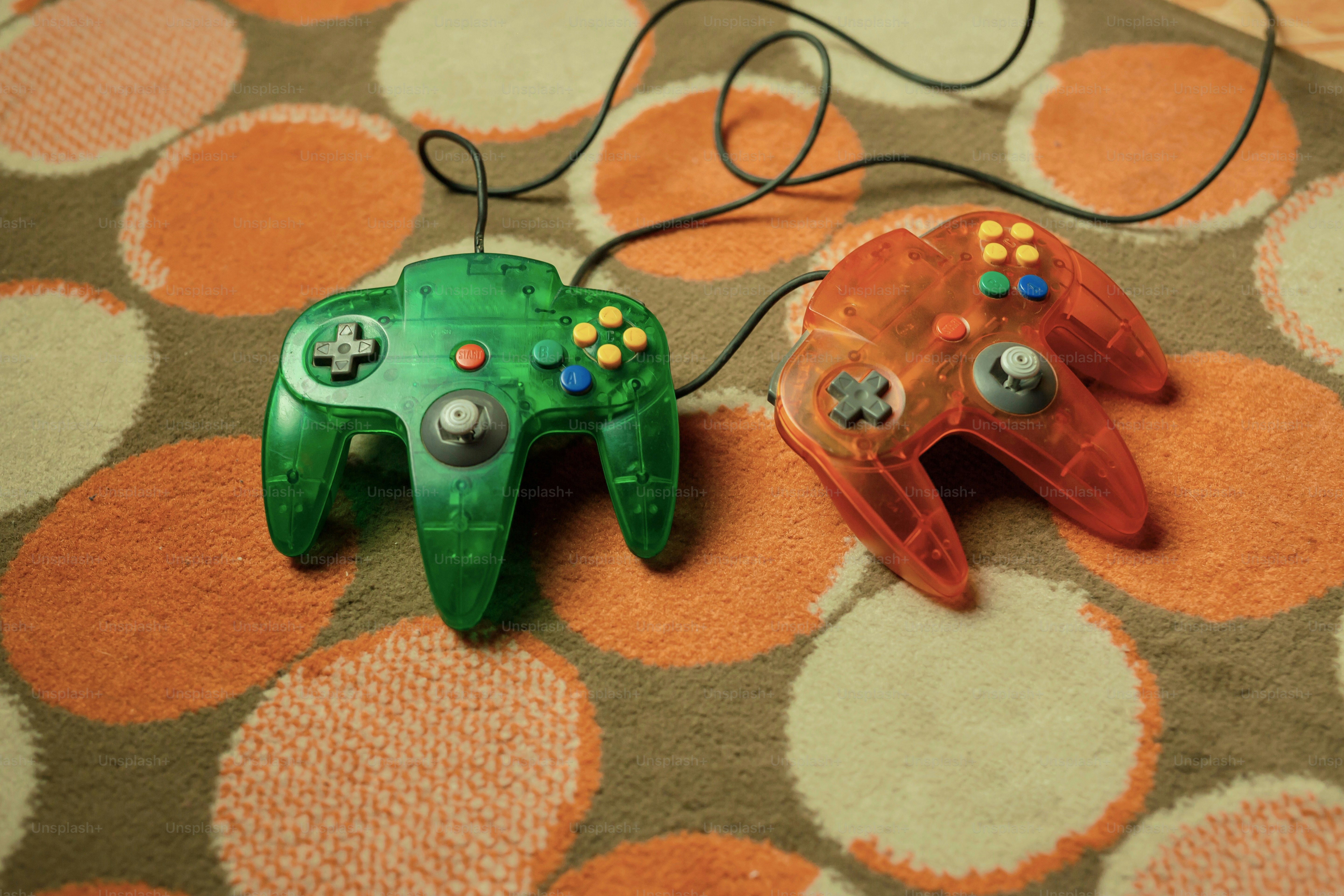 Two video game controllers sitting on top of a carpet photo – 90s Image ...