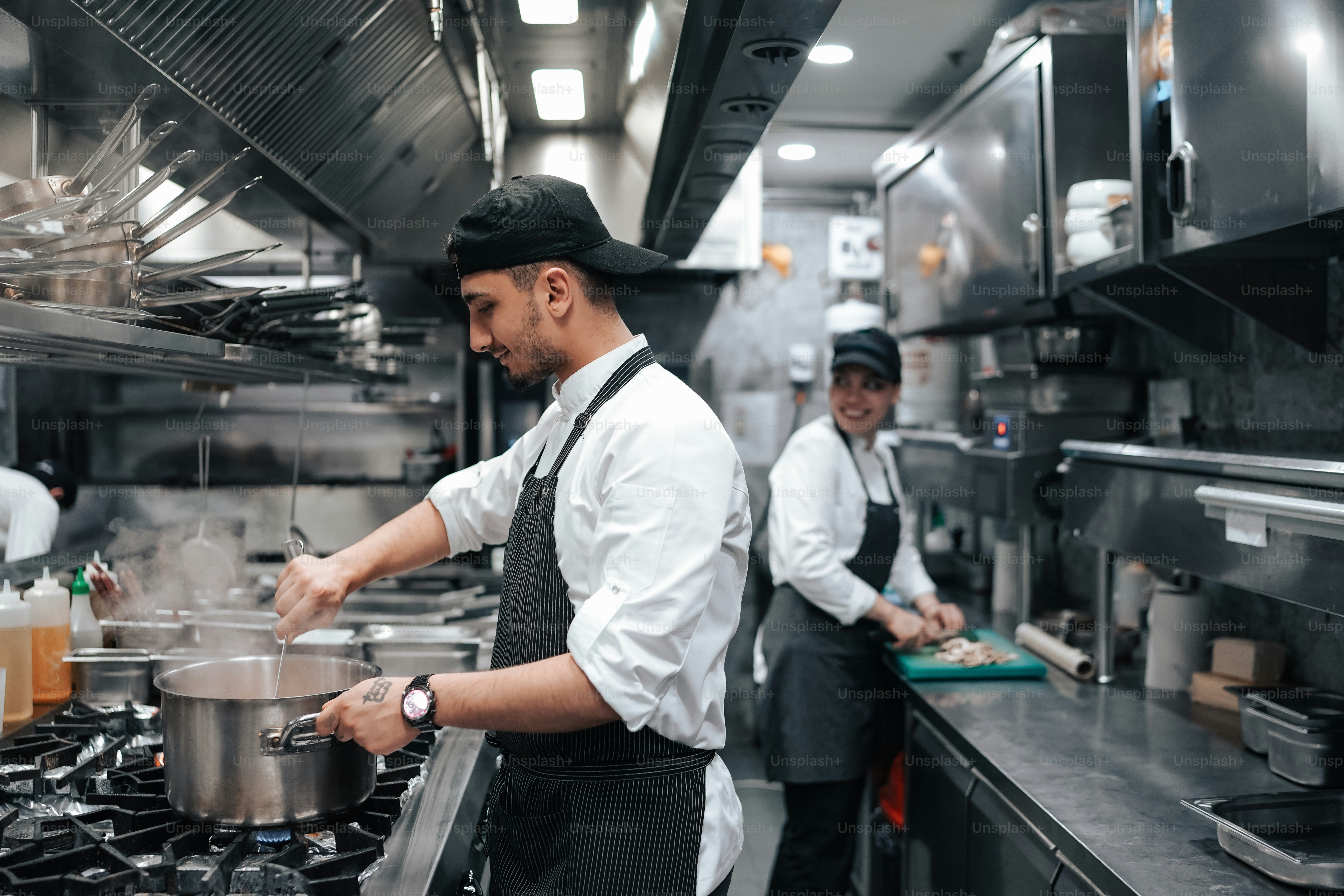 A man in a kitchen preparing food on top of a stove photo – Kitchen ...