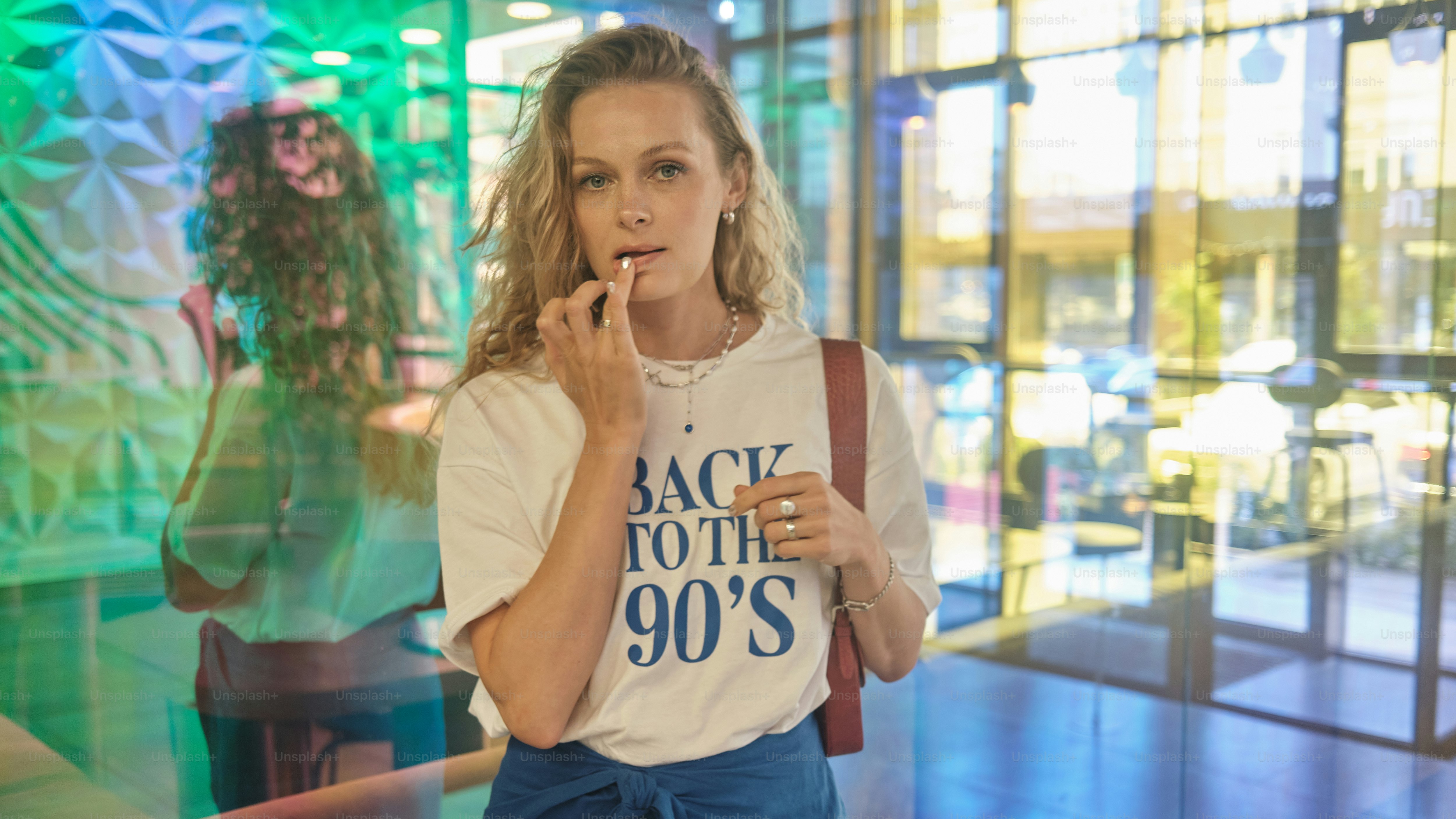 A woman standing in front of a glass wall smoking a cigarette photo ...