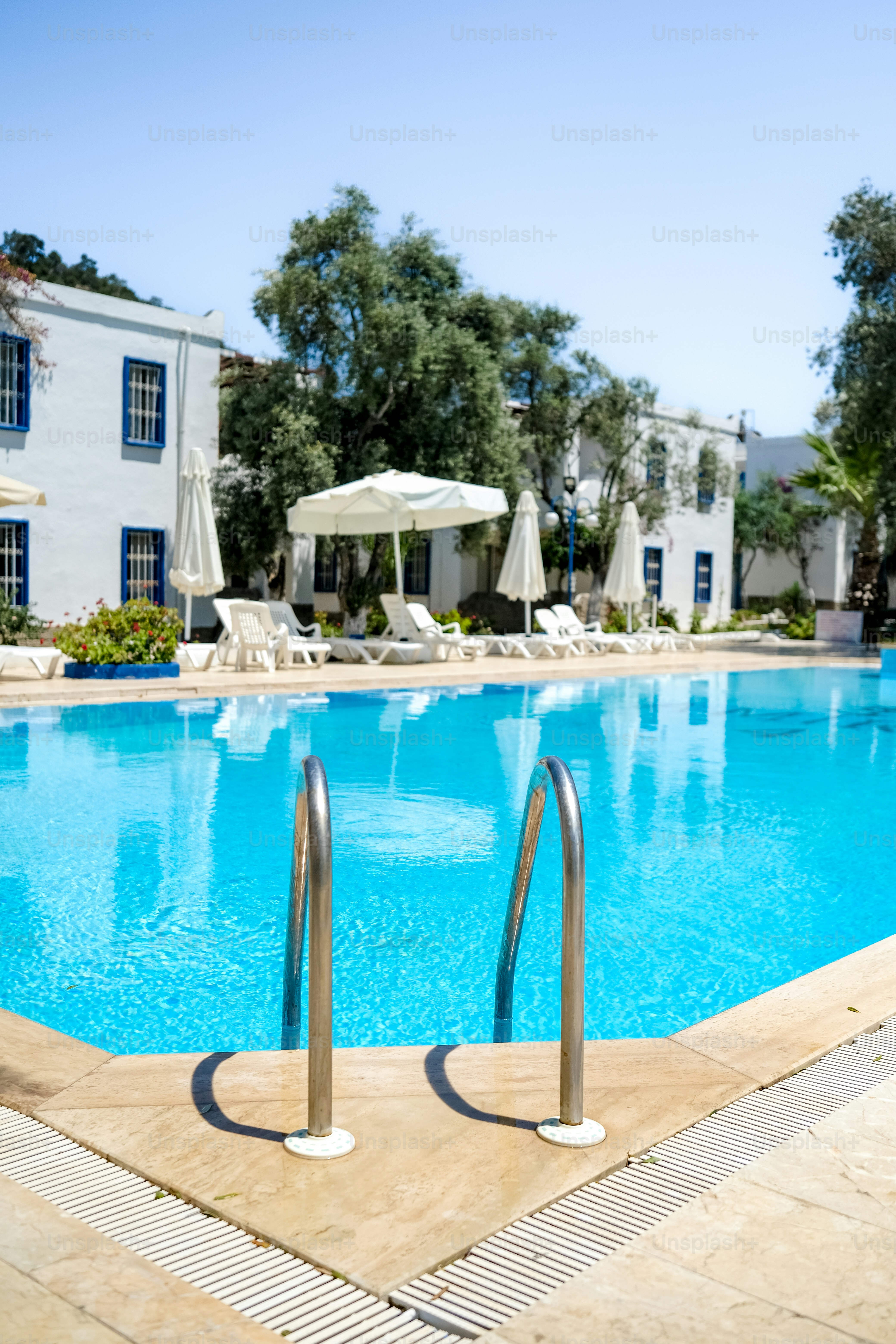 A large swimming pool with chairs and umbrellas photo – Rental Image on ...