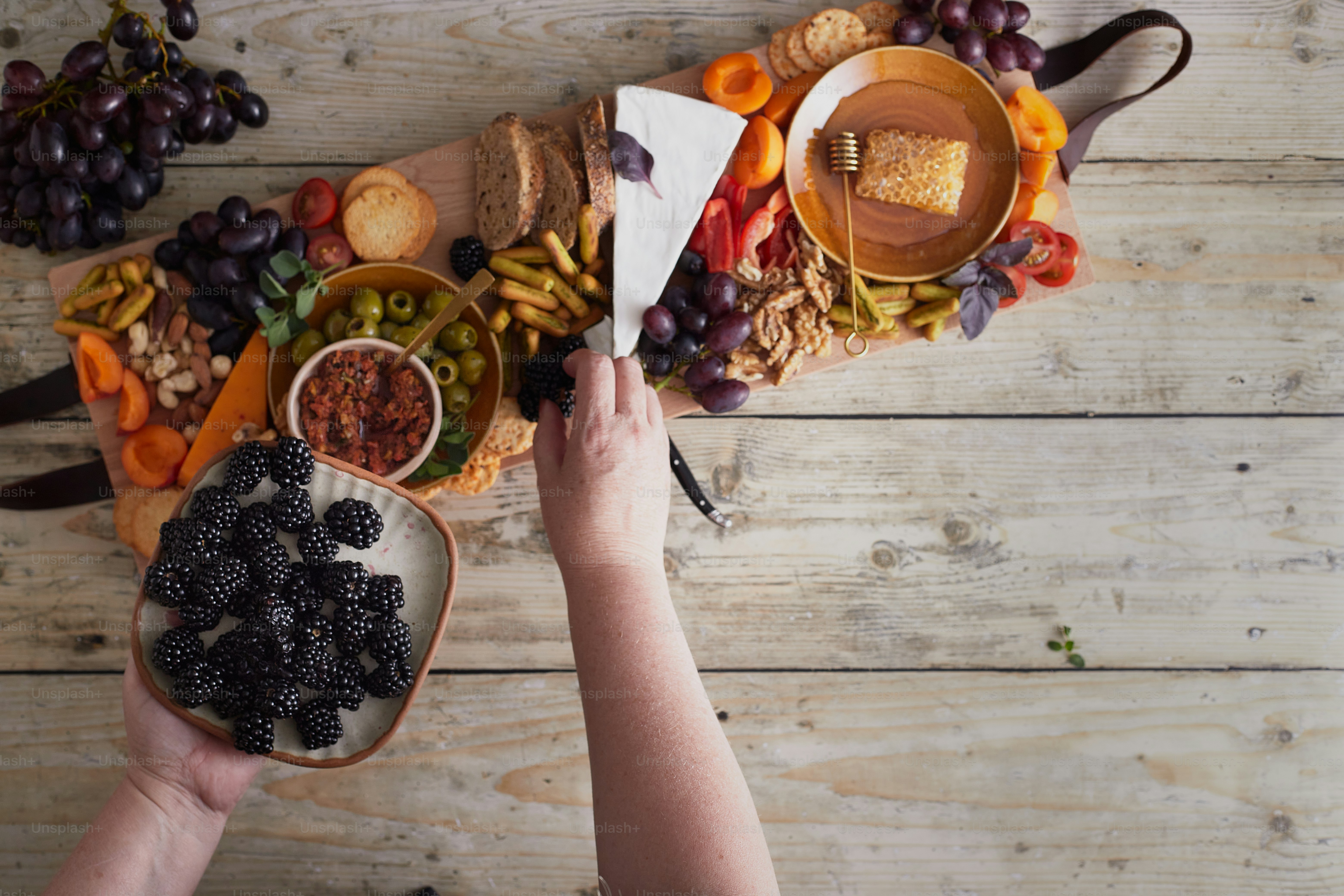 A person holding a plate of food in front of a platter of fruit and ...