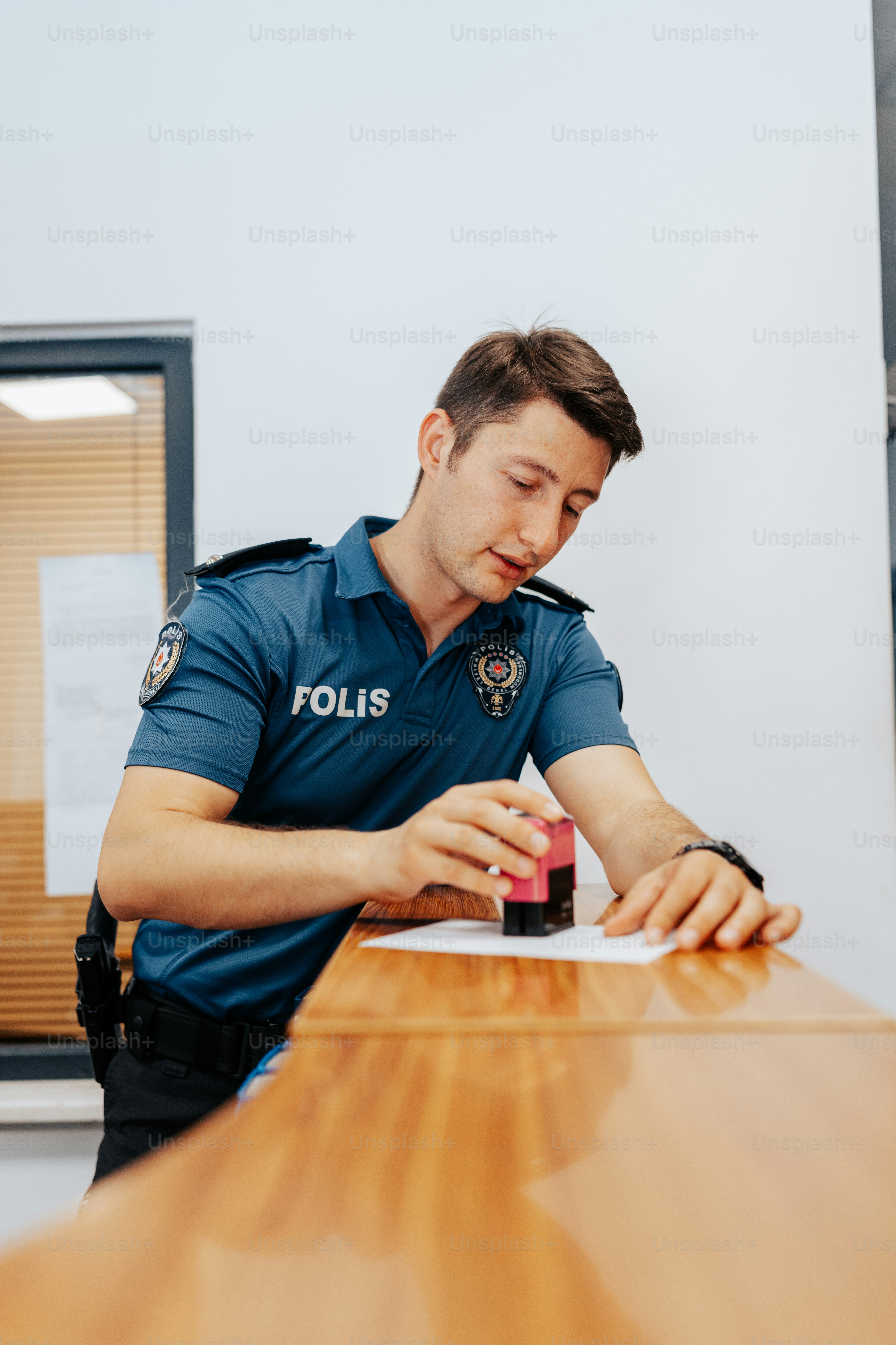 A police officer sitting at a table writing on a piece of paper photo ...