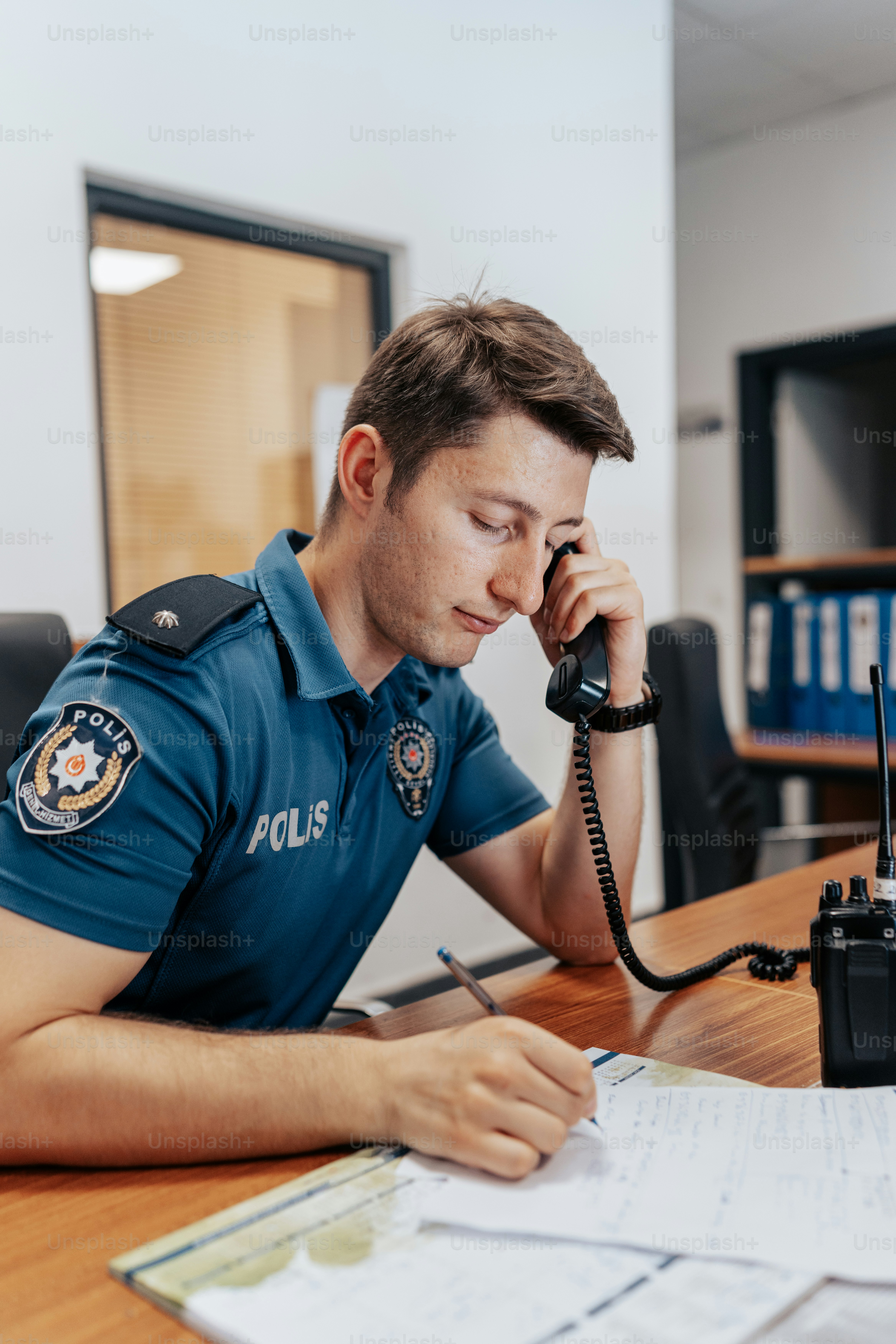 A police officer sitting at a table writing on a piece of paper photo ...