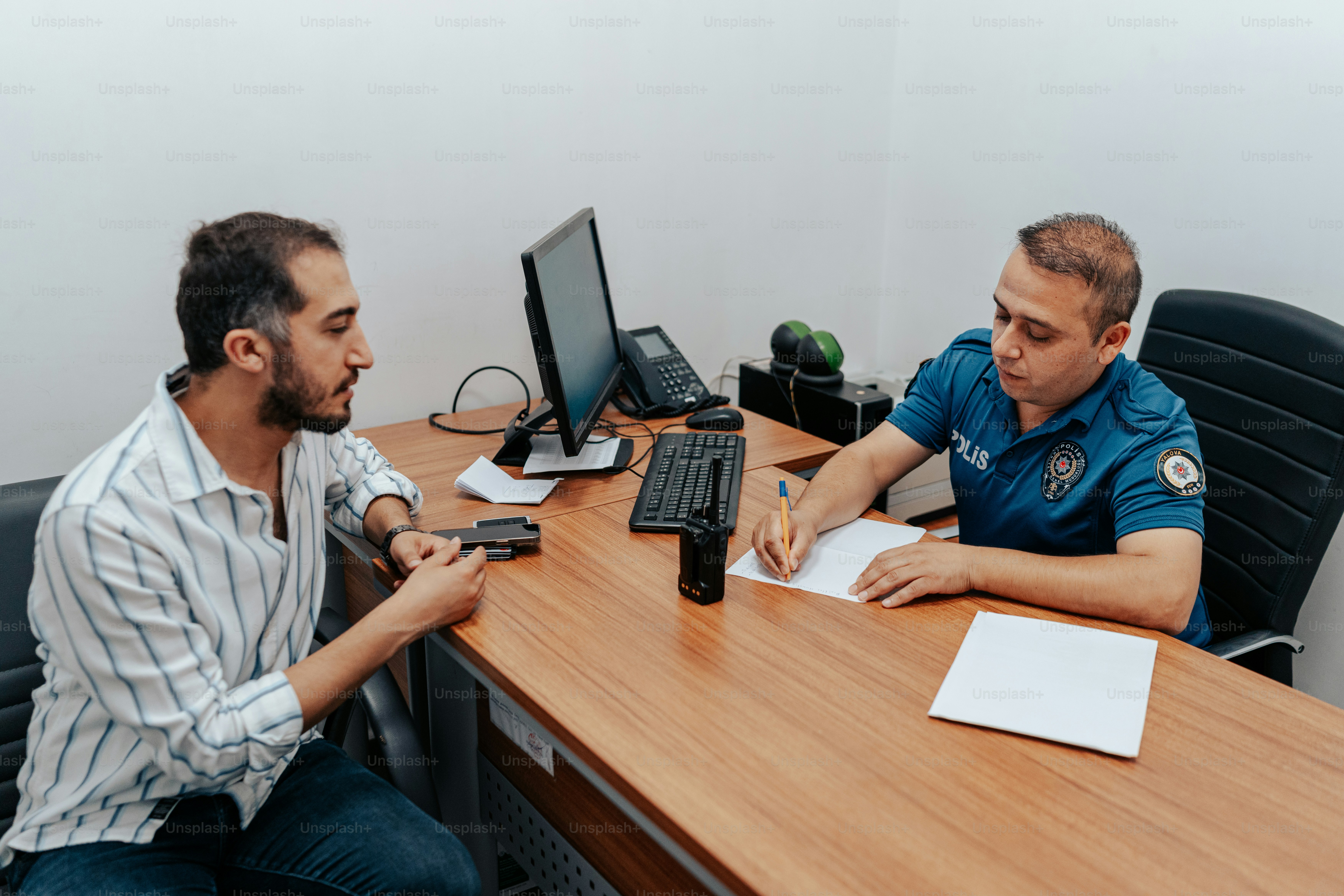 A police officer sitting at a desk in an office photo – Police Image on ...