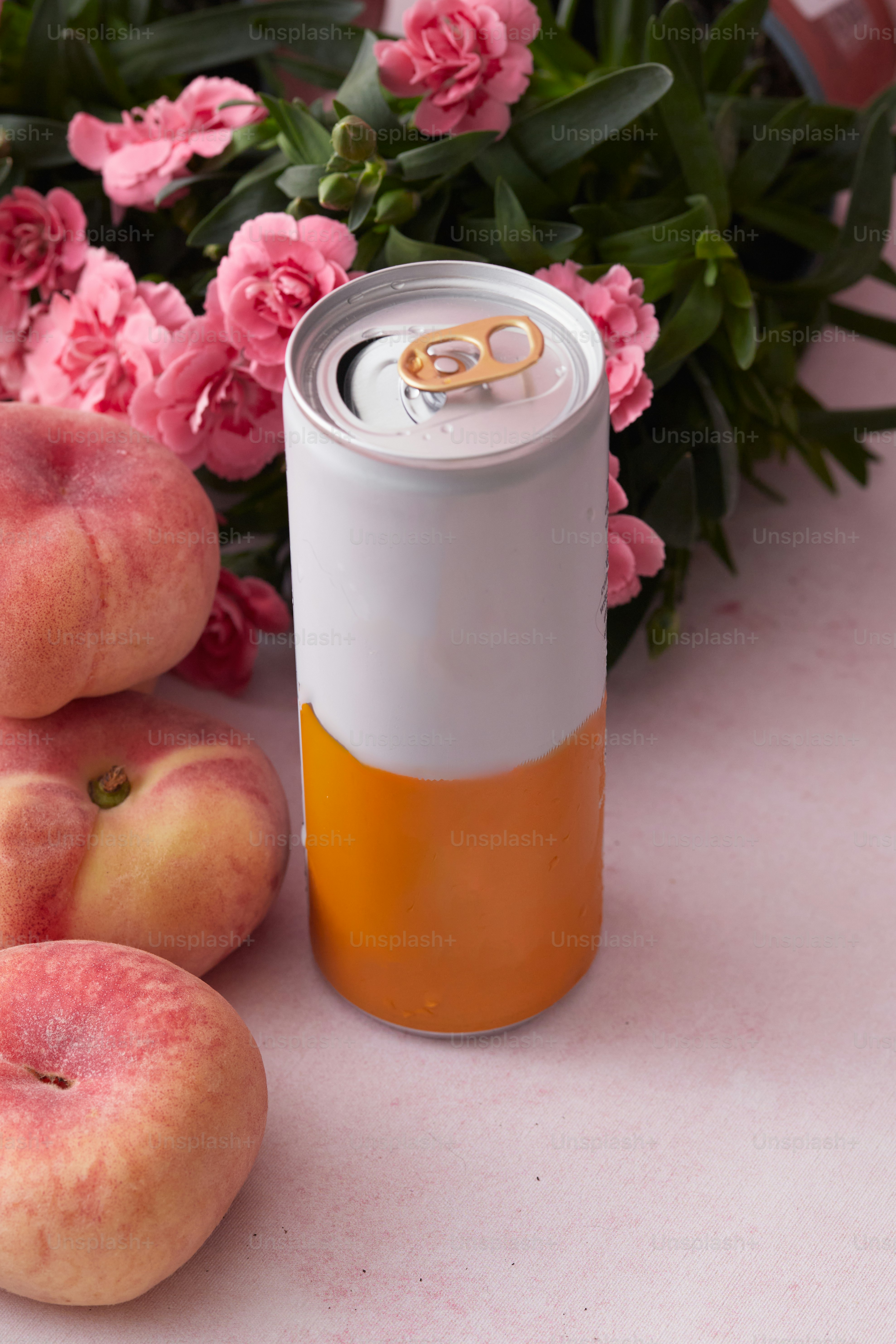 A can of apple cider next to peaches and flowers photo – Canned drink ...
