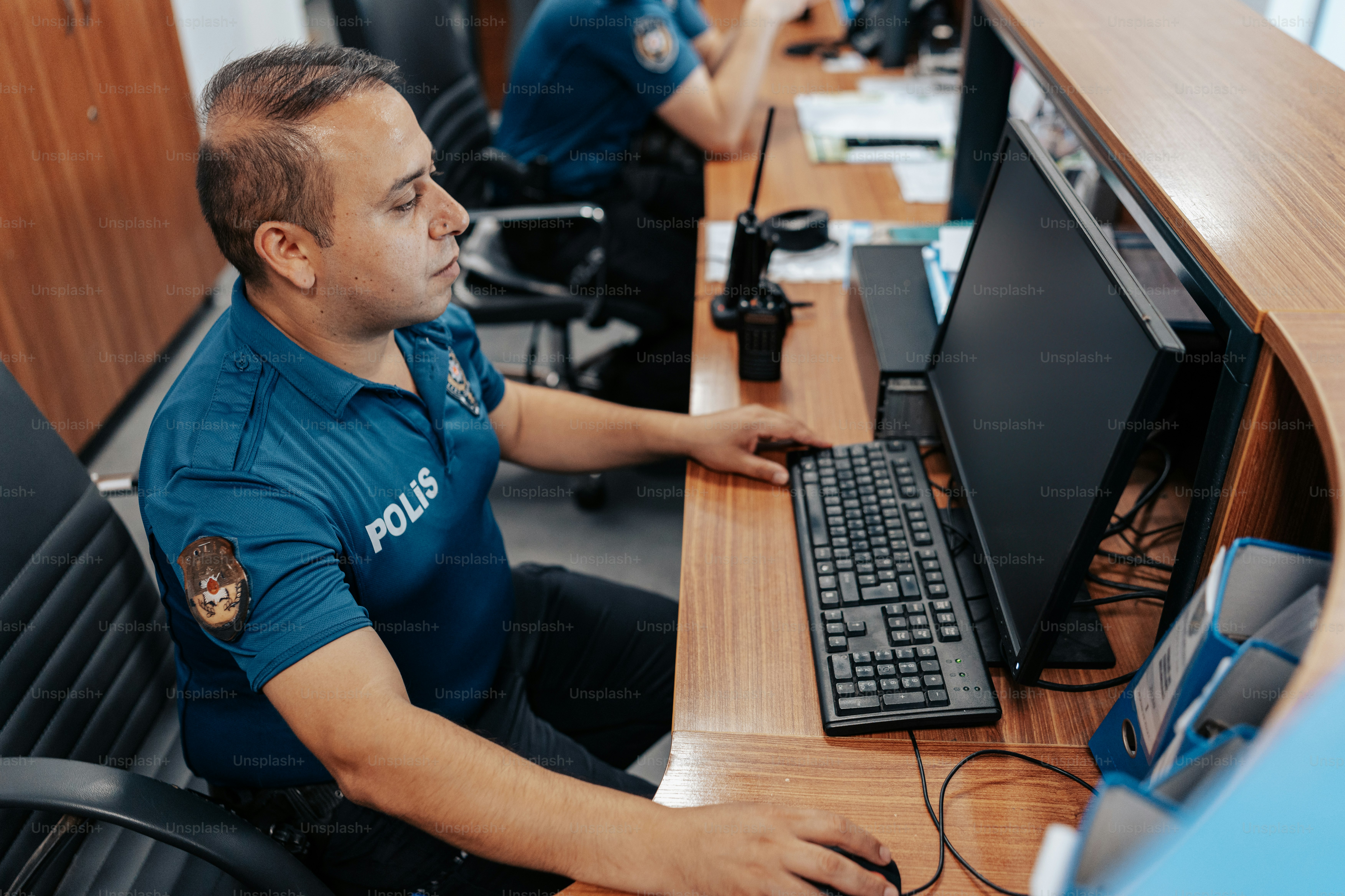 A police officer sitting in front of a computer photo – Police station ...
