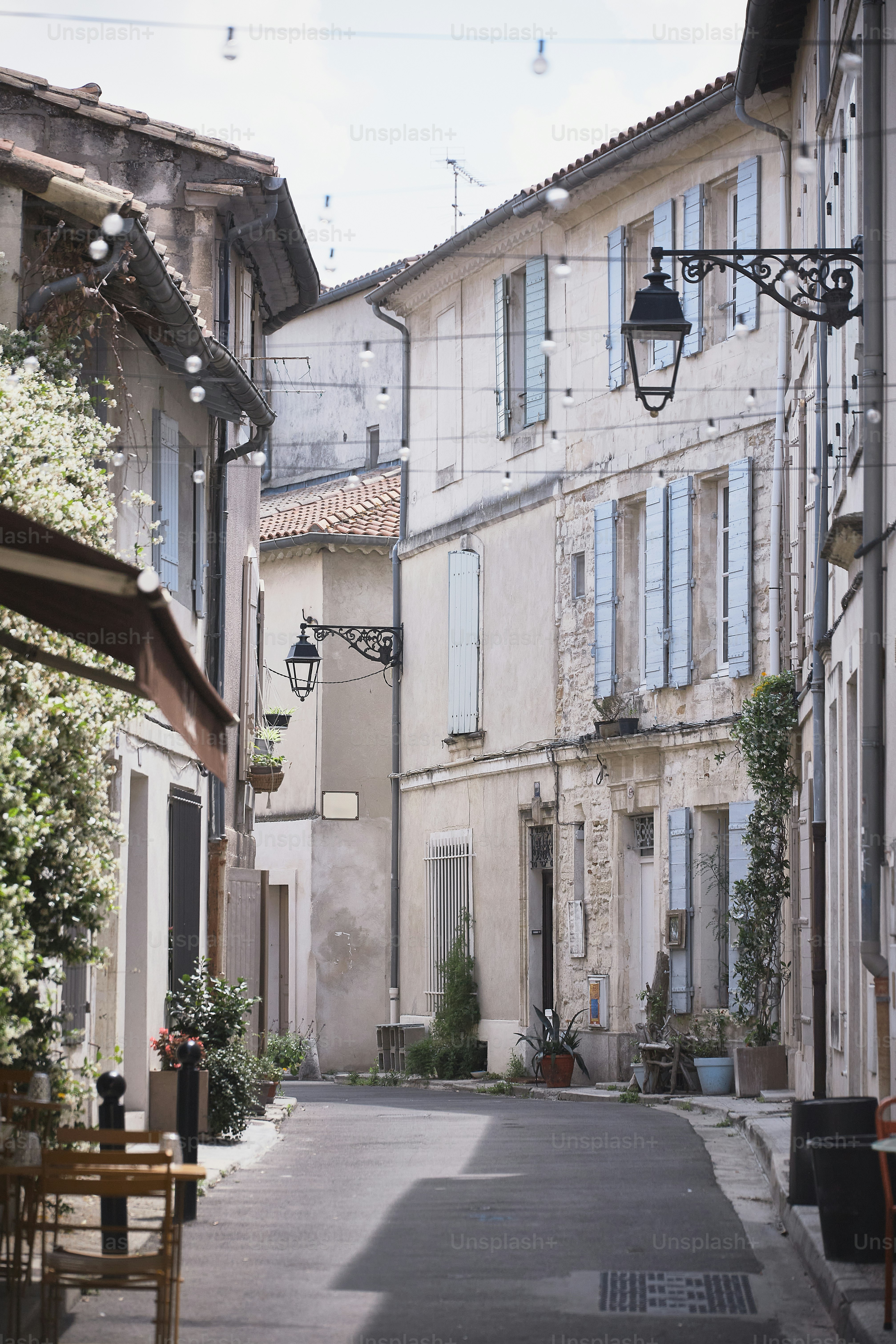 A narrow street with tables and chairs on both sides photo – Arles ...