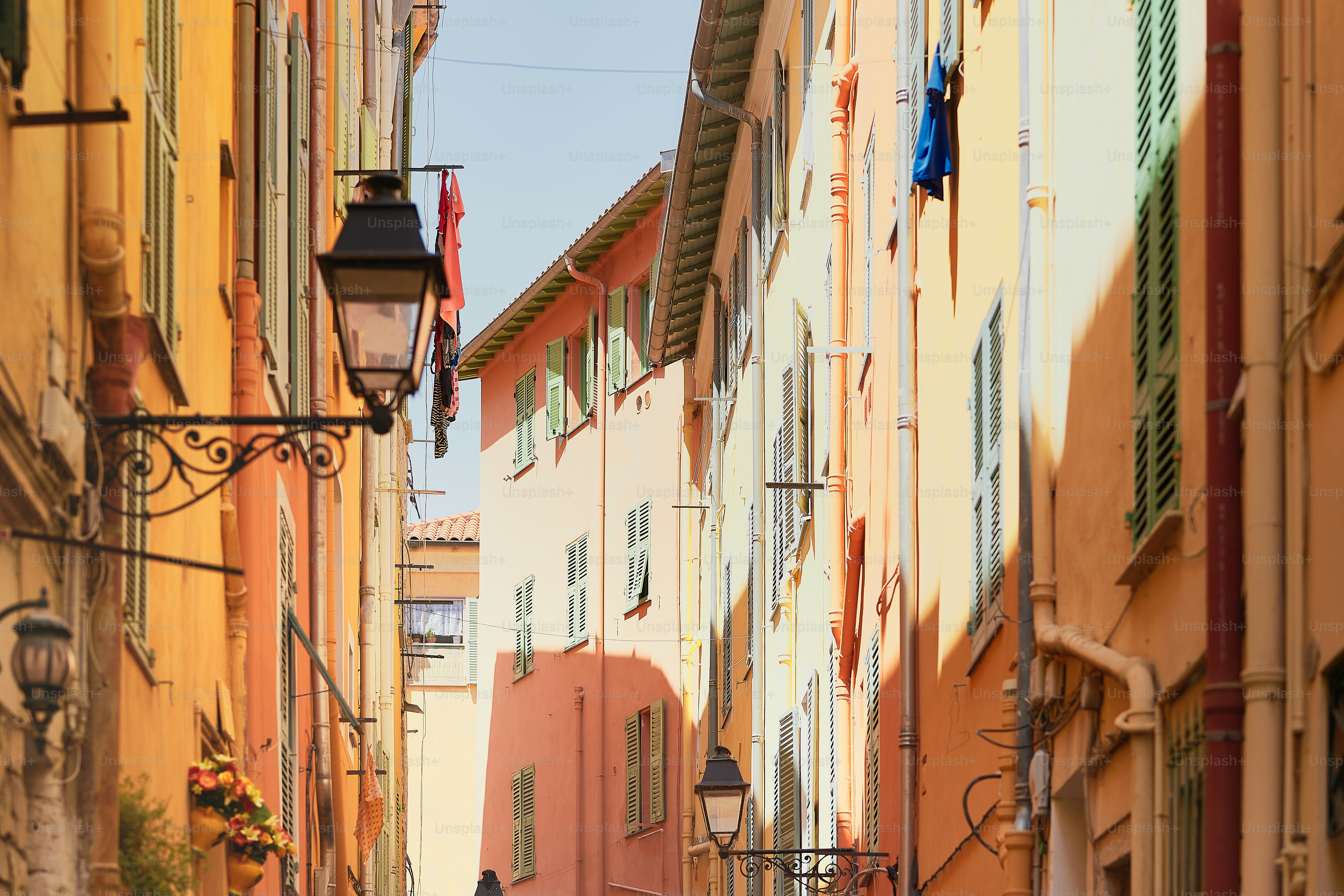 A narrow city street lined with tall buildings photo – Menton Image on ...