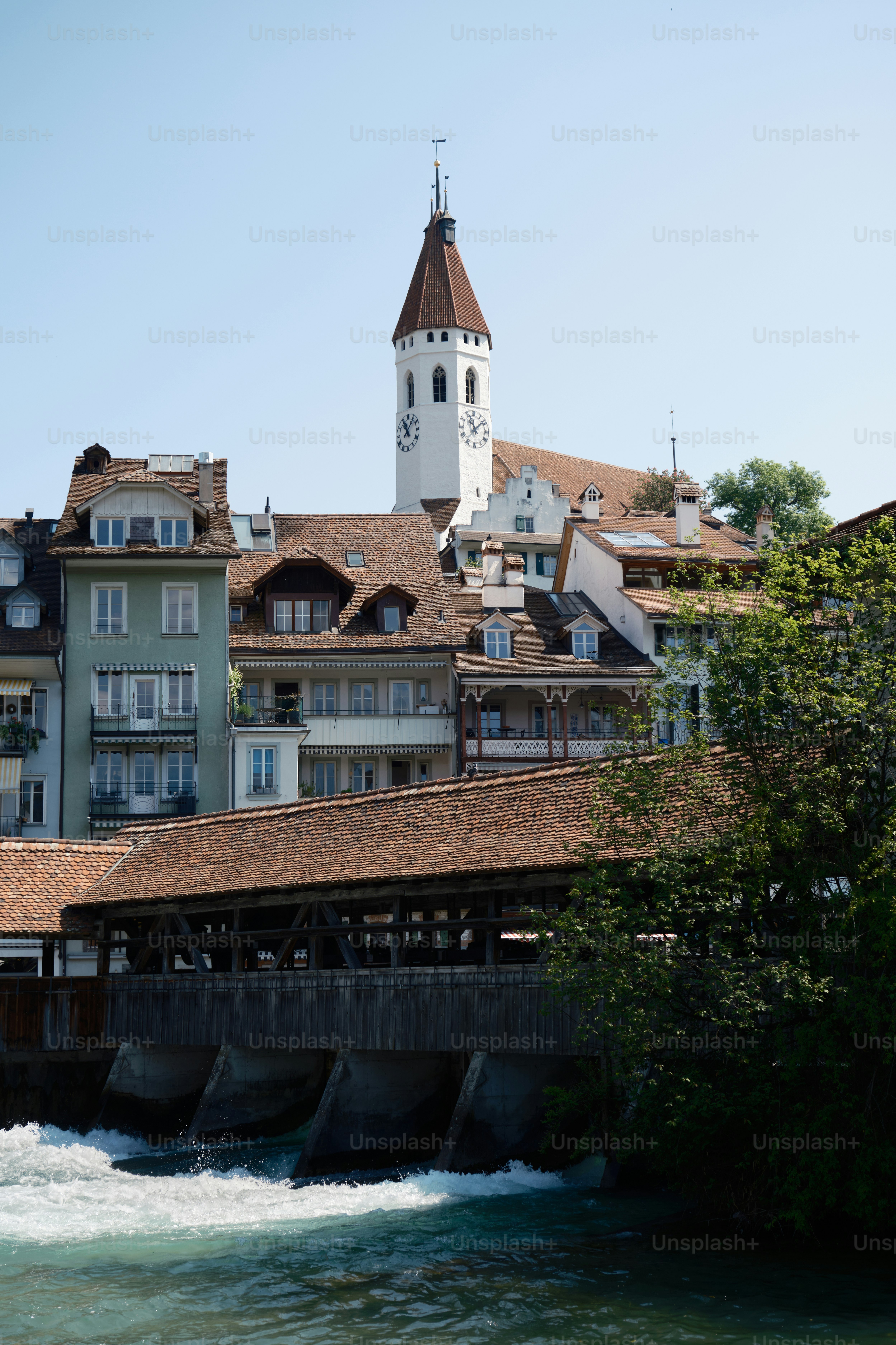 Un edificio con una torre de reloj junto a un río foto – Imagen de ...