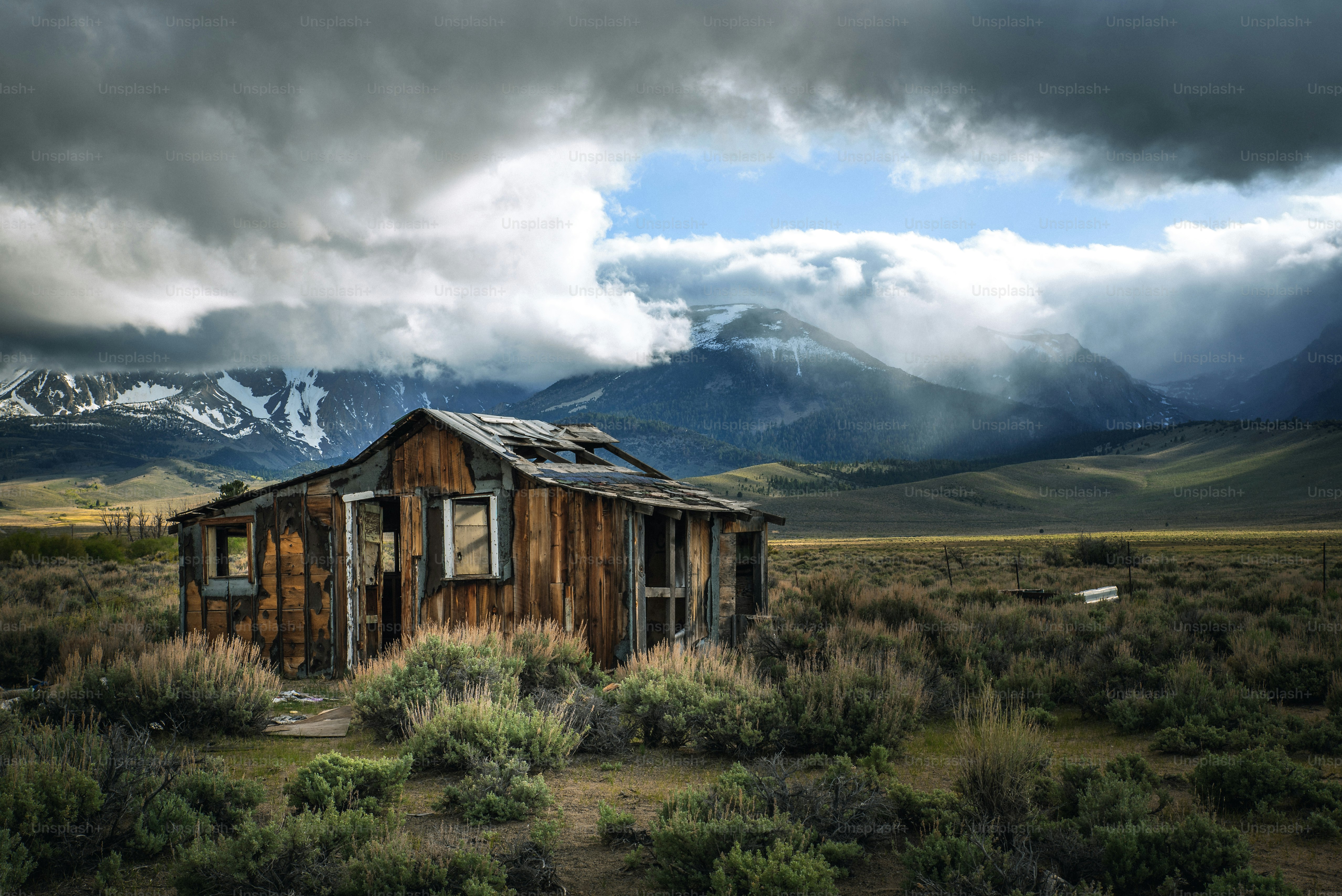 An old shack in a field with mountains in the background photo – Usa ...