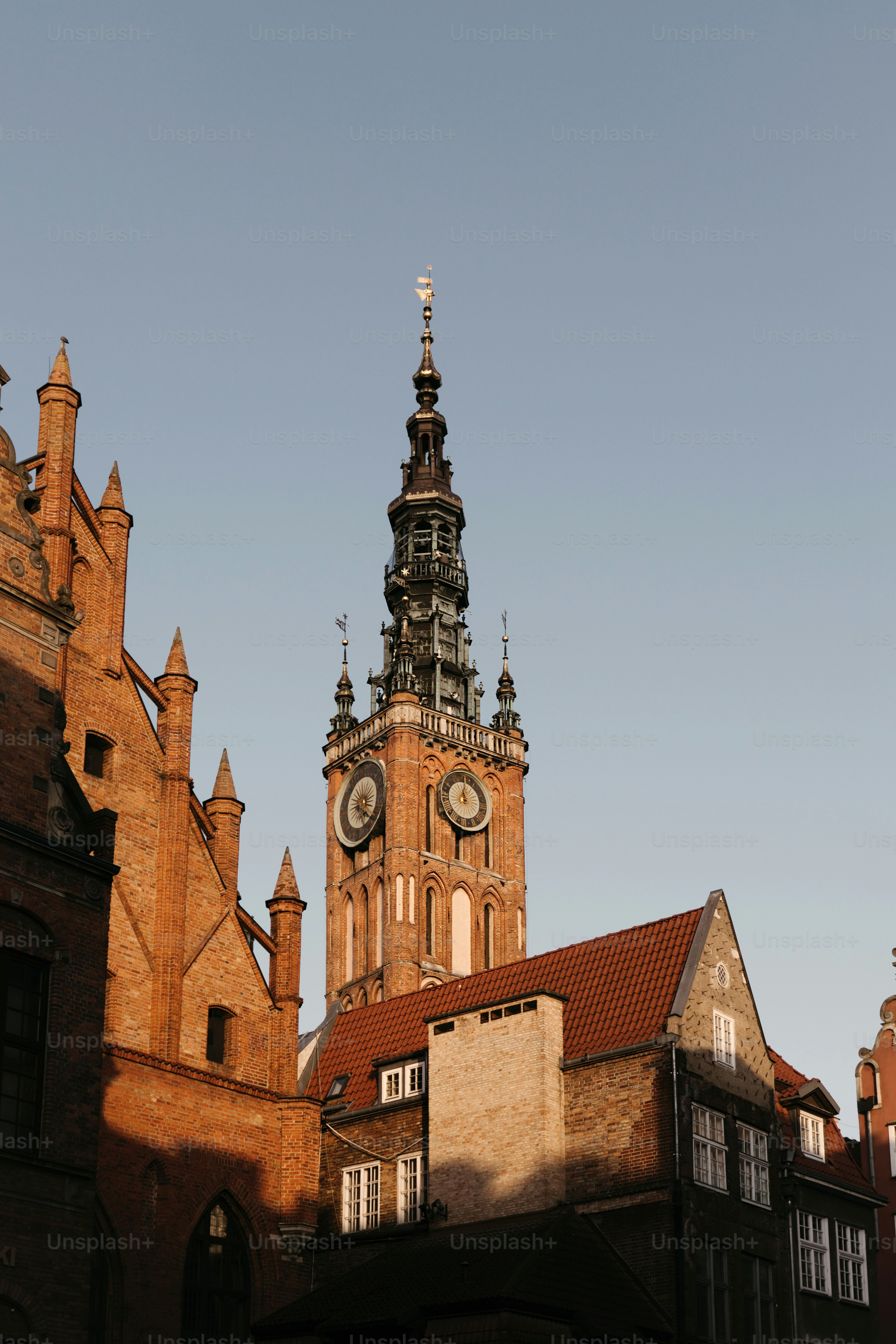 An arch in a brick building with a clock tower in the background photo ...