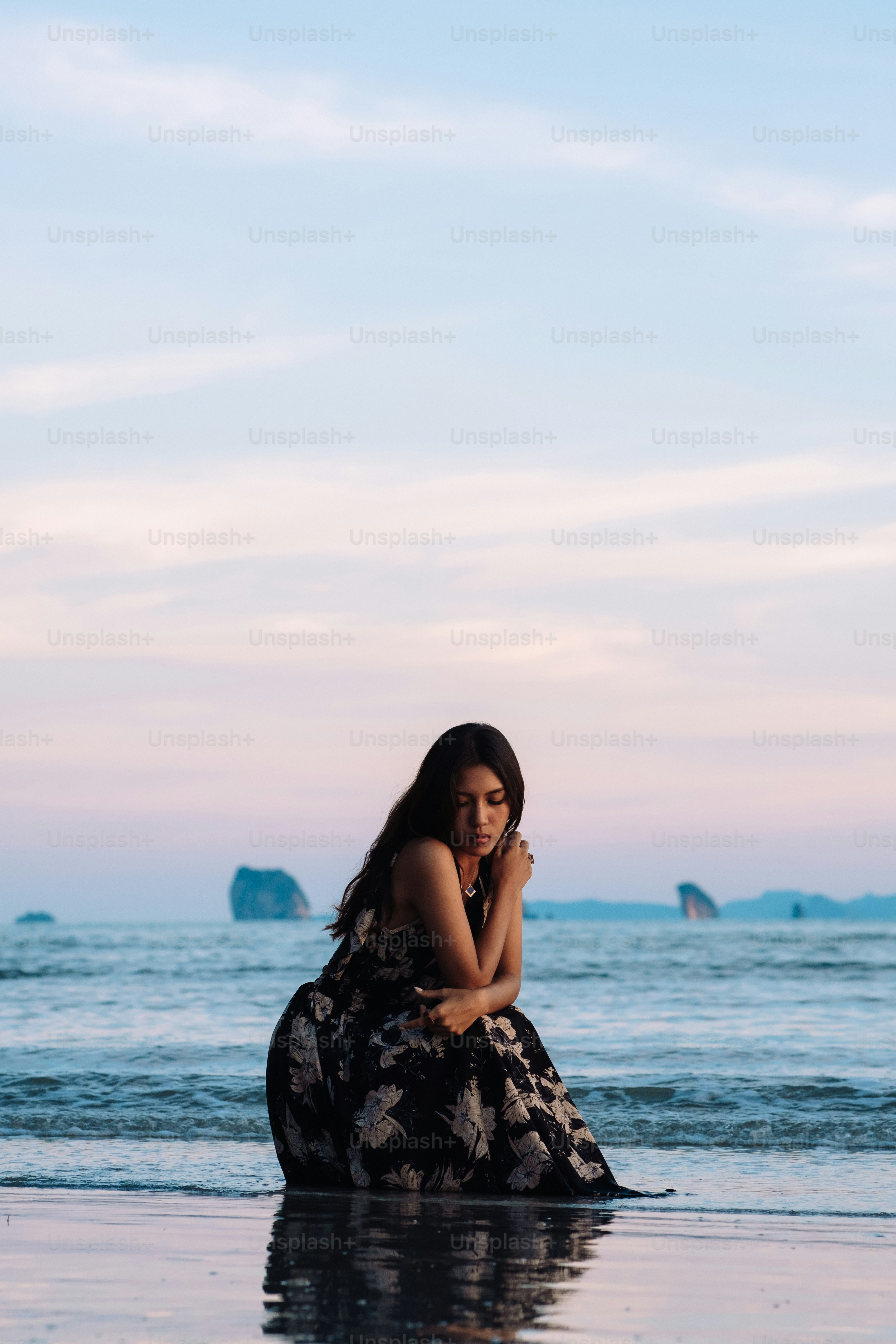 A woman standing on a beach next to the ocean photo – Lonely Image on ...