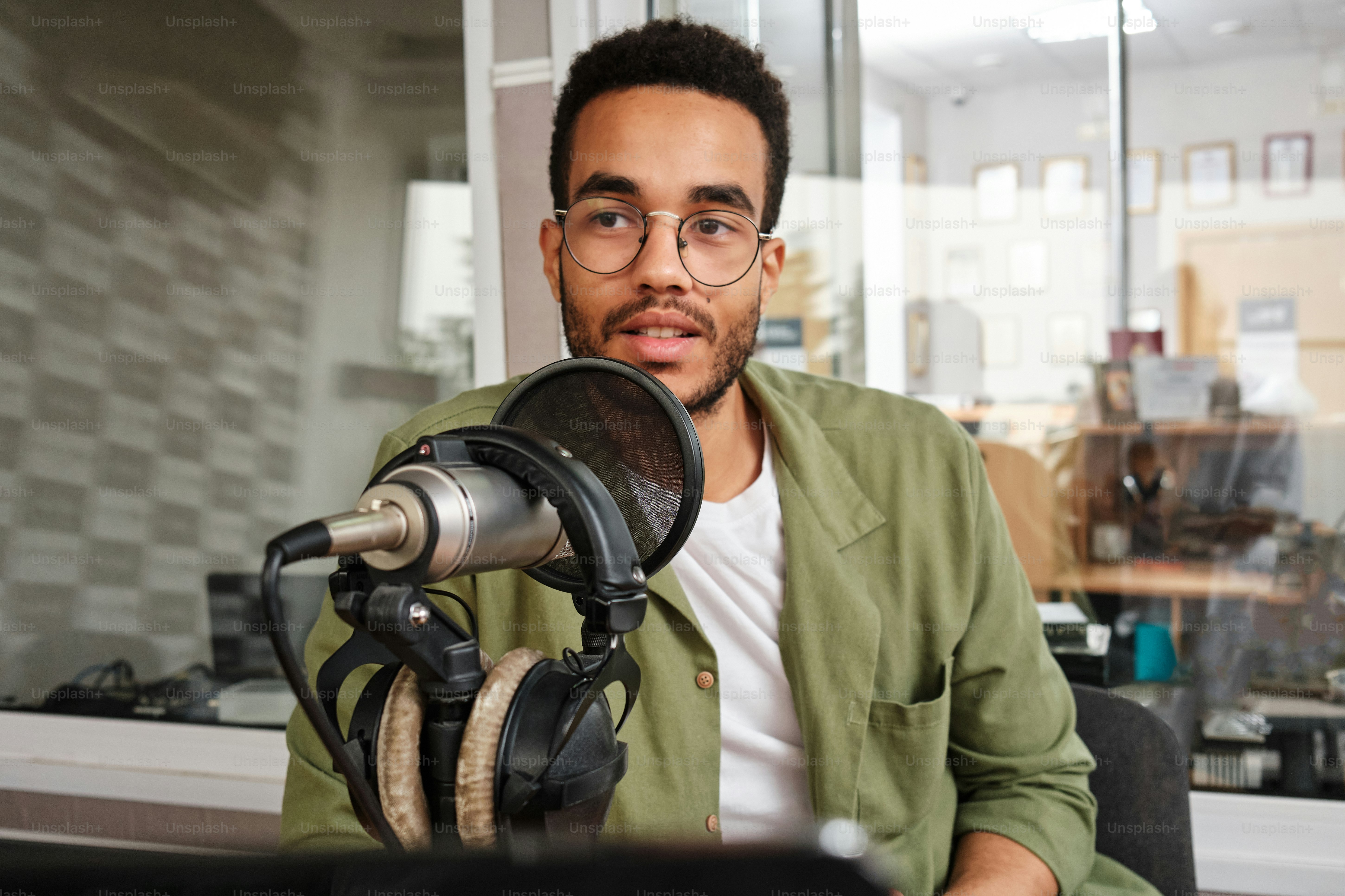 A man sitting at a desk in front of a microphone photo – Broadcasting ...