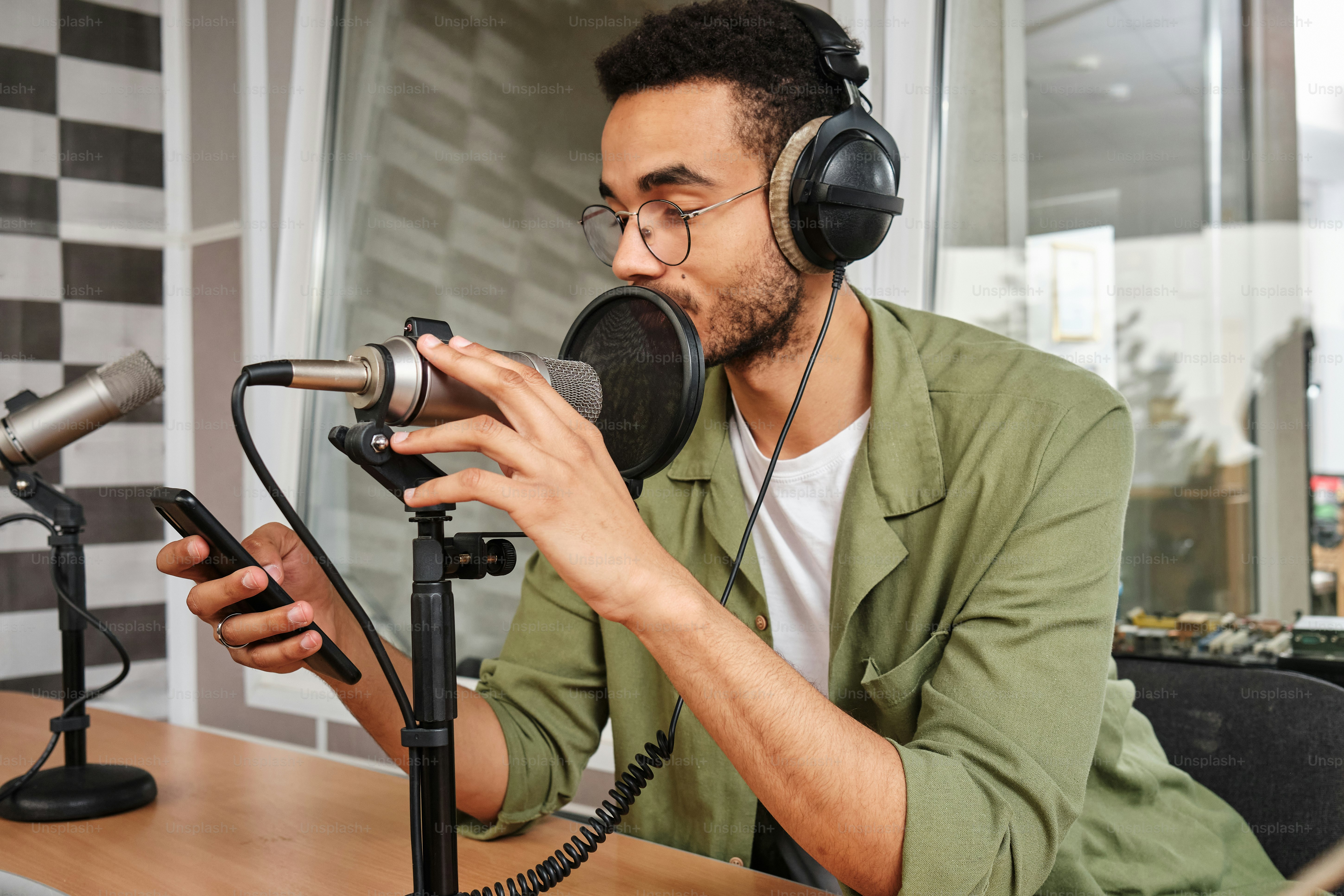 A man sitting in front of a microphone with headphones on photo ...