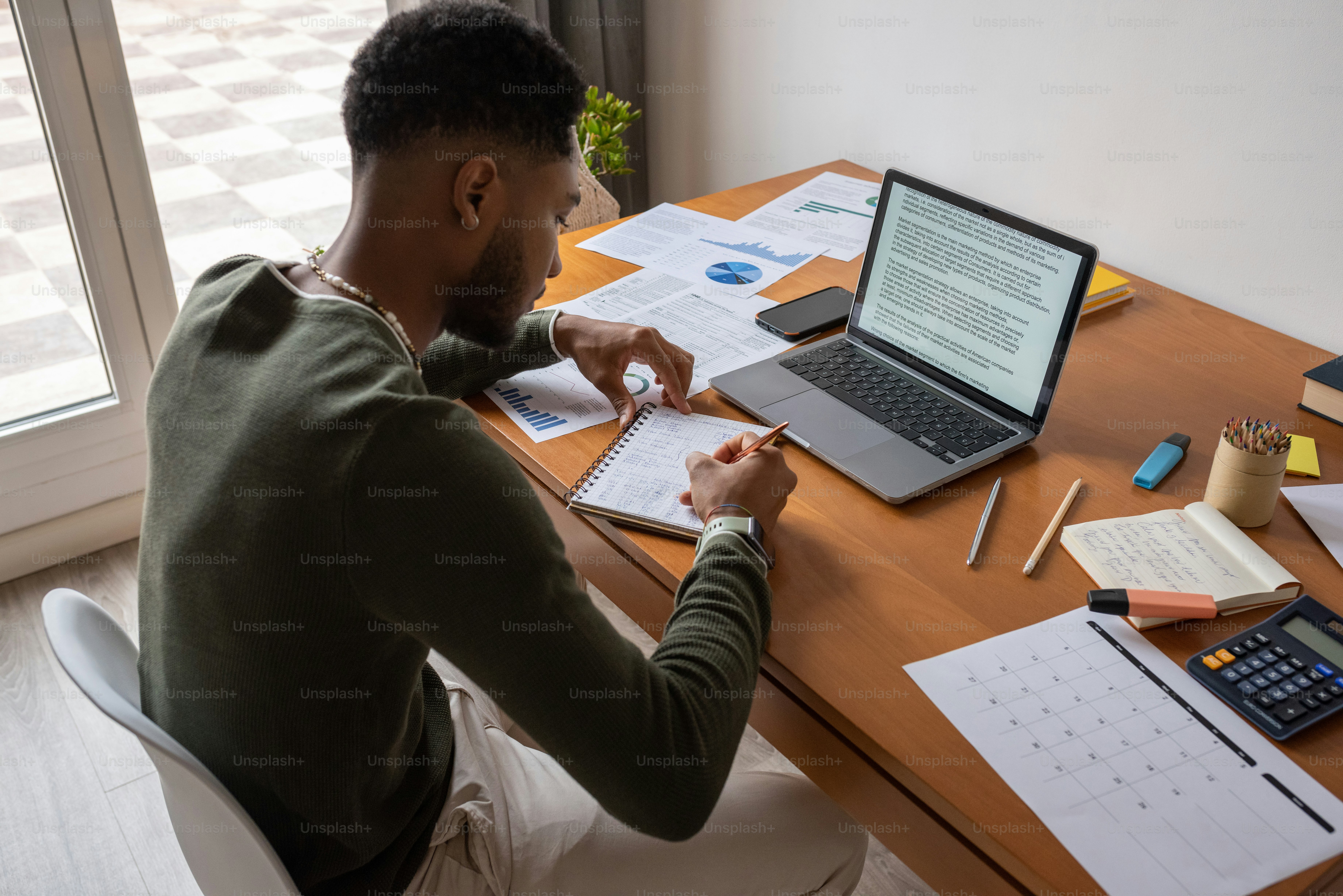 A man sitting at a desk with papers and a laptop photo – Finance Image ...
