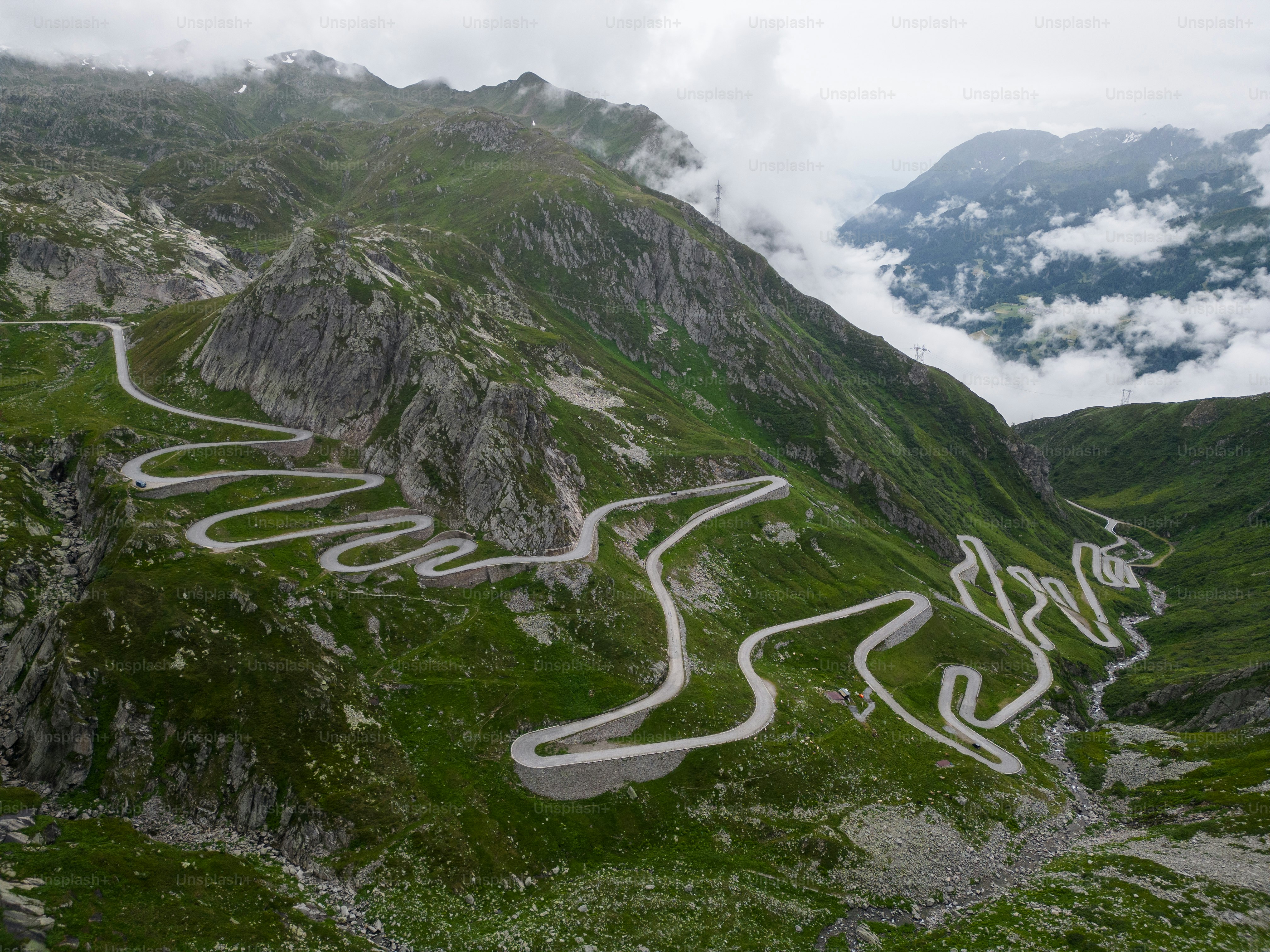 A winding road in the mountains on a cloudy day photo – Switzerland ...