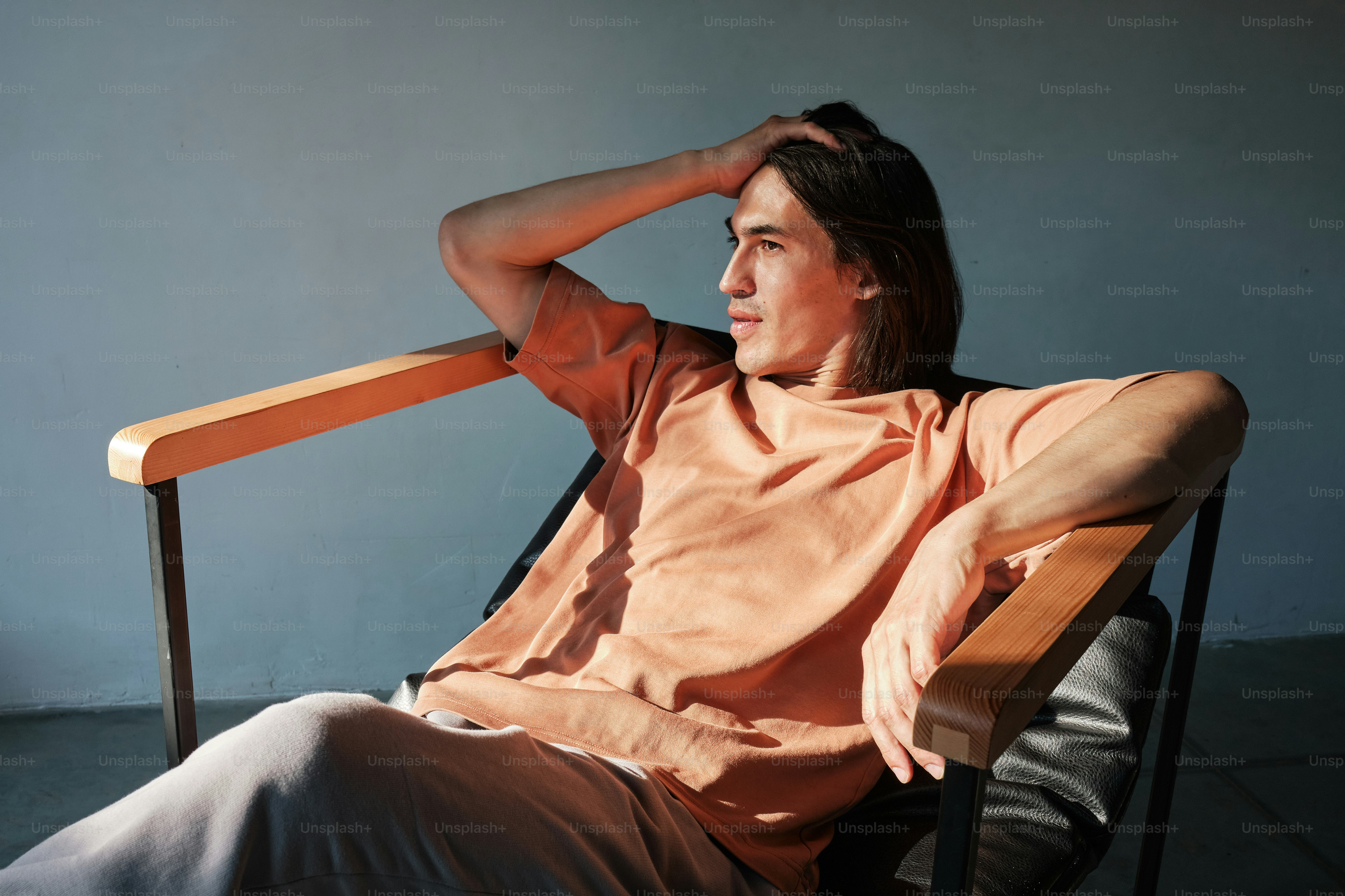 A man sitting in a chair with his hand on his head photo – T shirt ...