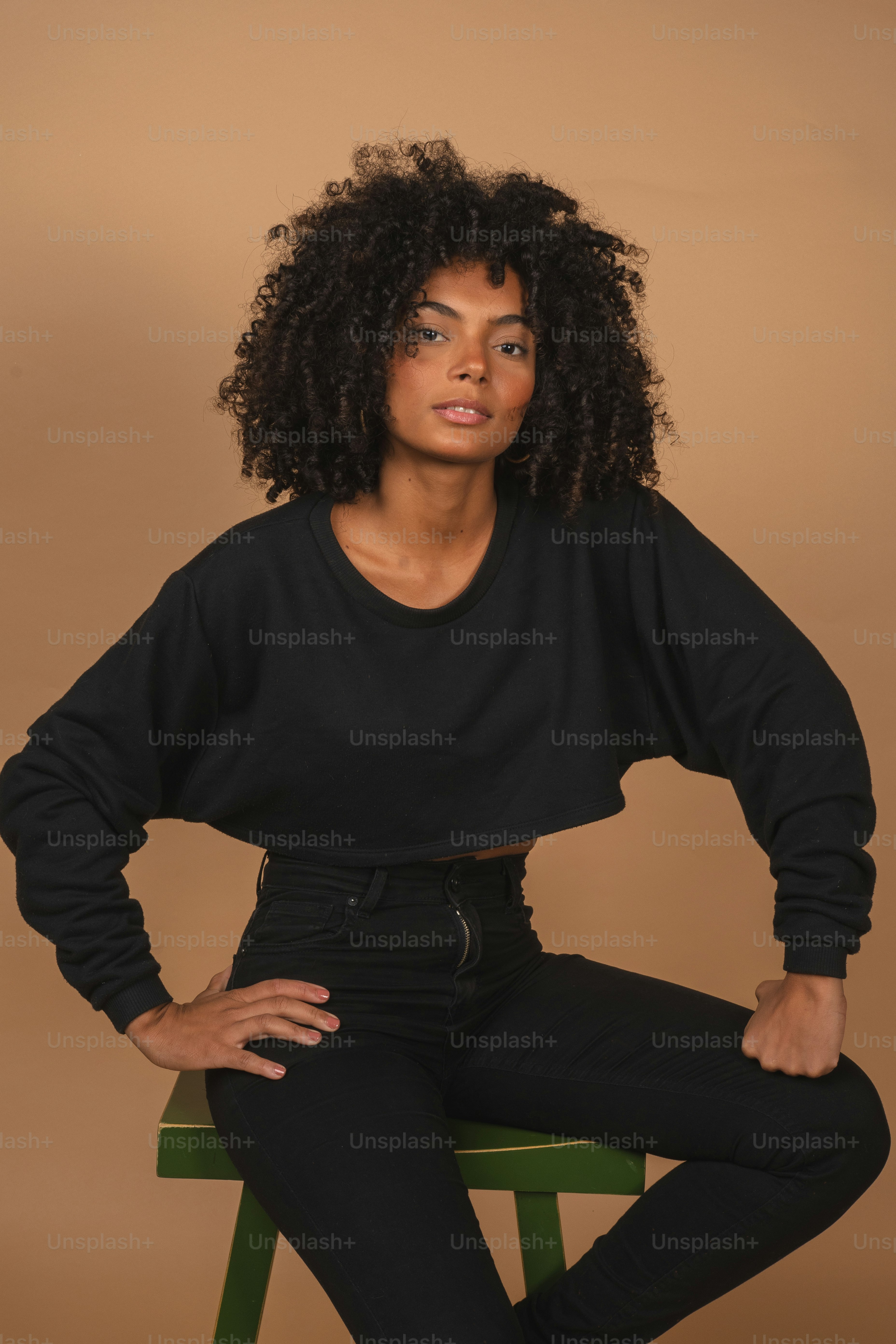 A woman sitting on a stool with her hands on her hips photo – Basic ...
