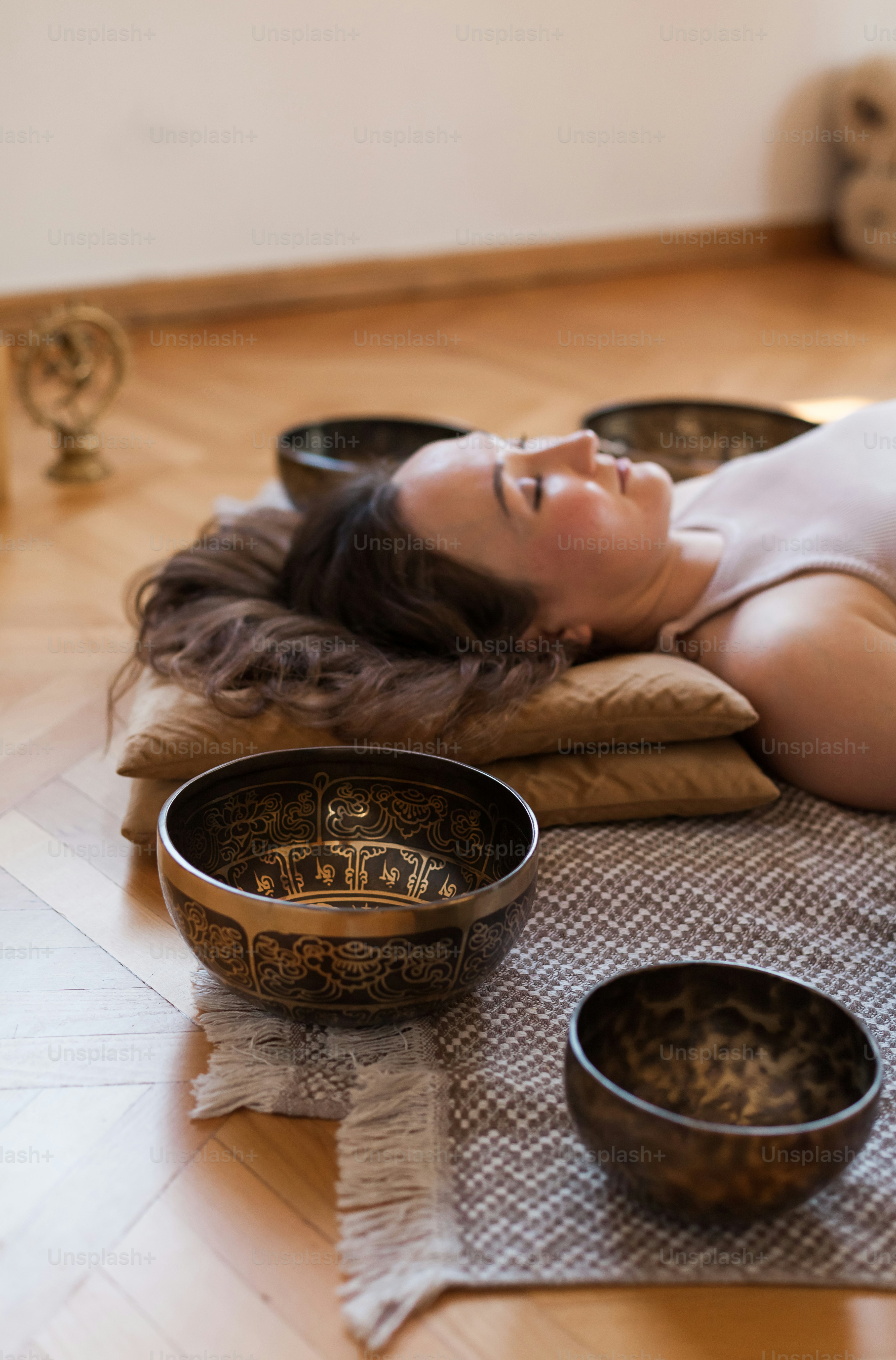 A woman laying on a mat with bowls around her photo – Sound Healing ...