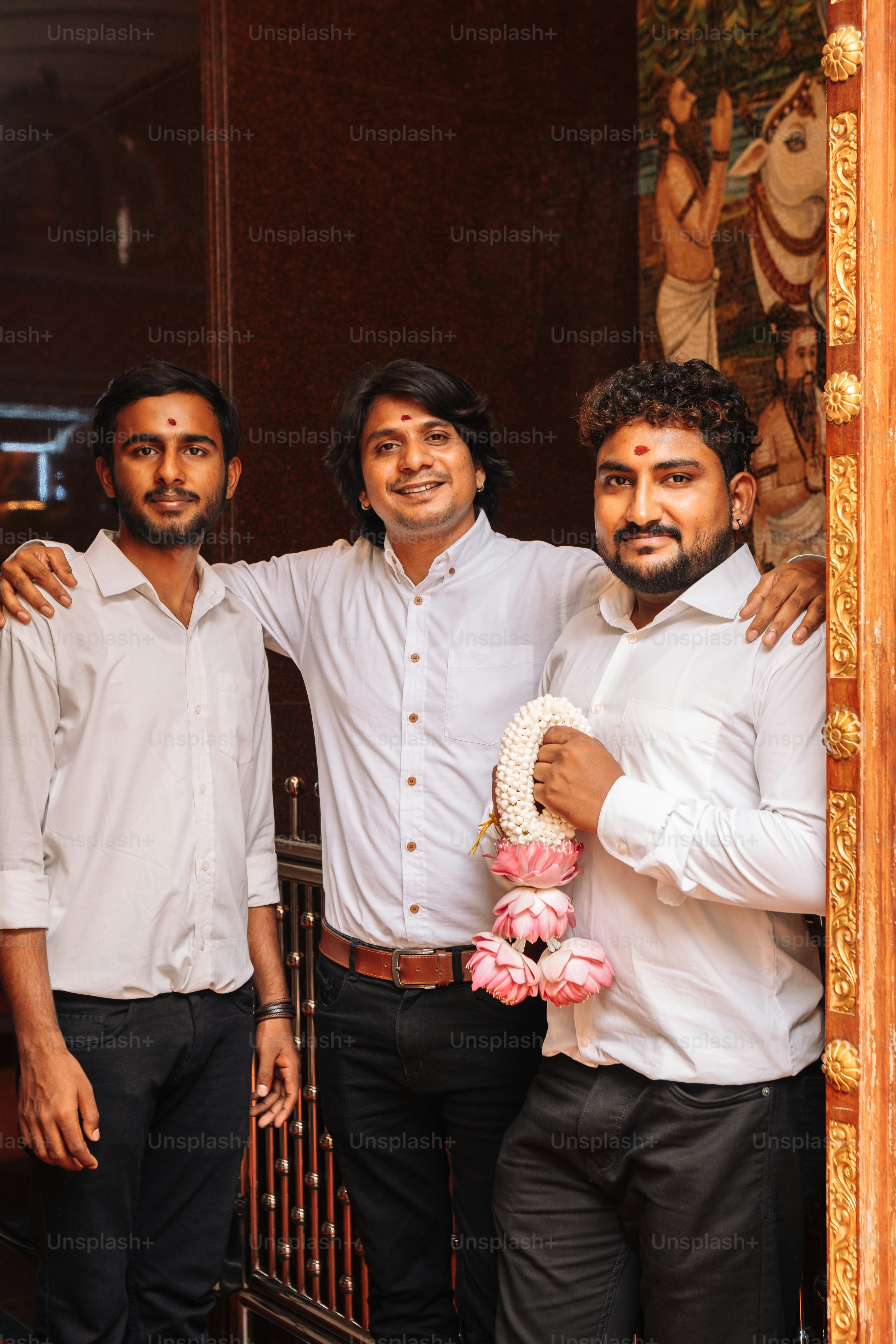 A group of three men standing next to each other photo – Man Image on ...