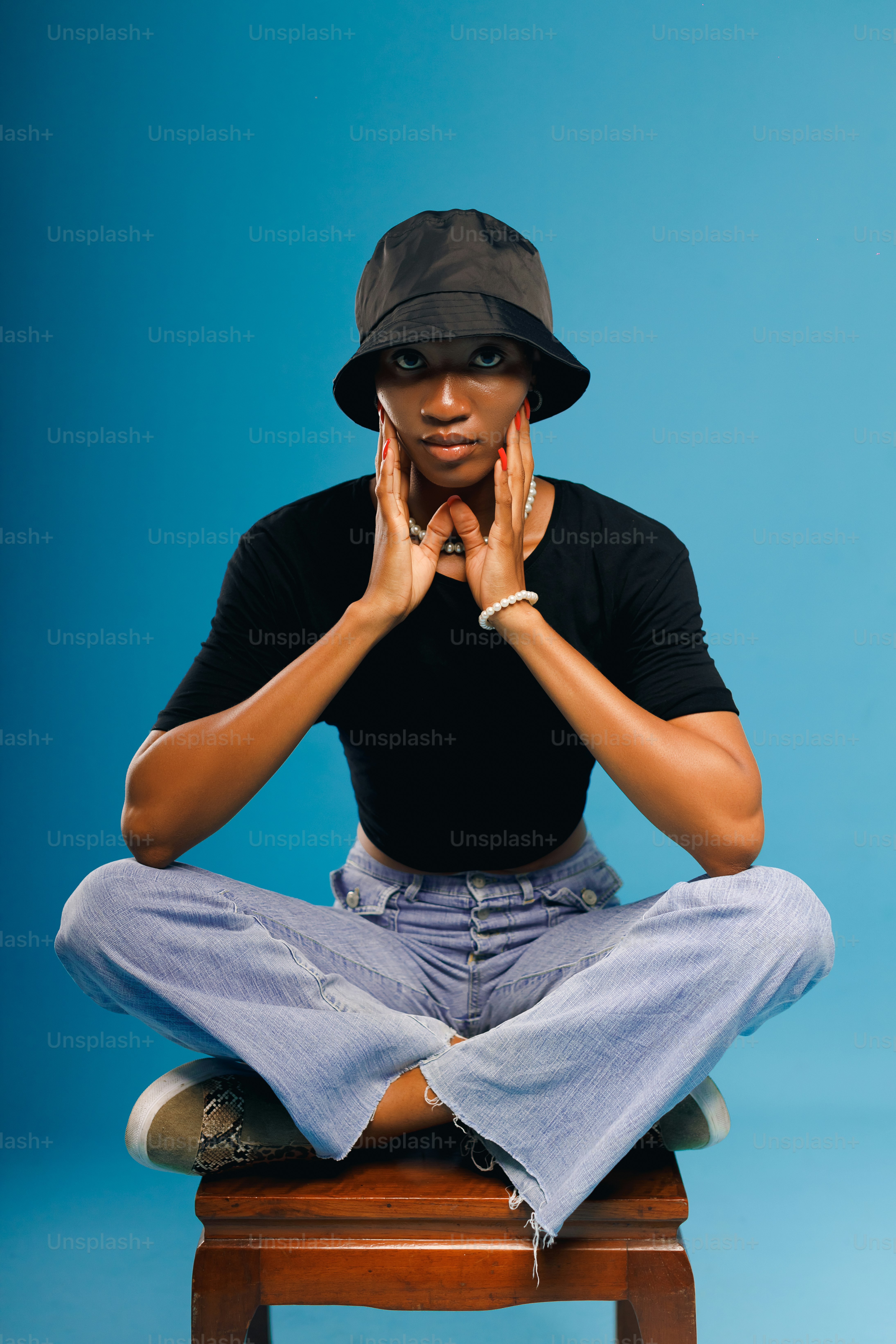 A person sitting on a stool with their hands together photo – T shirt ...