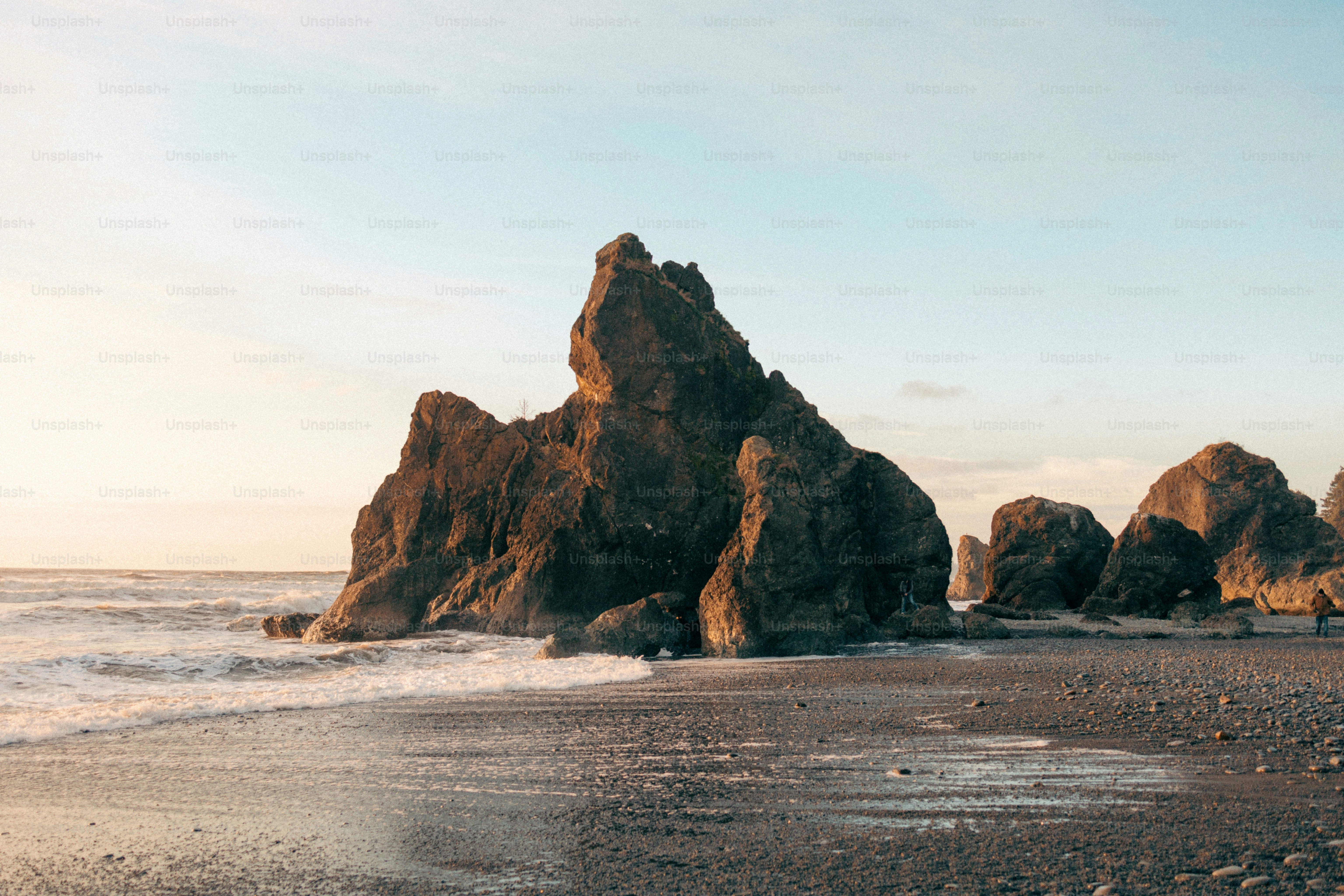 Una gran formación rocosa sentada en la cima de una playa de arena foto ...
