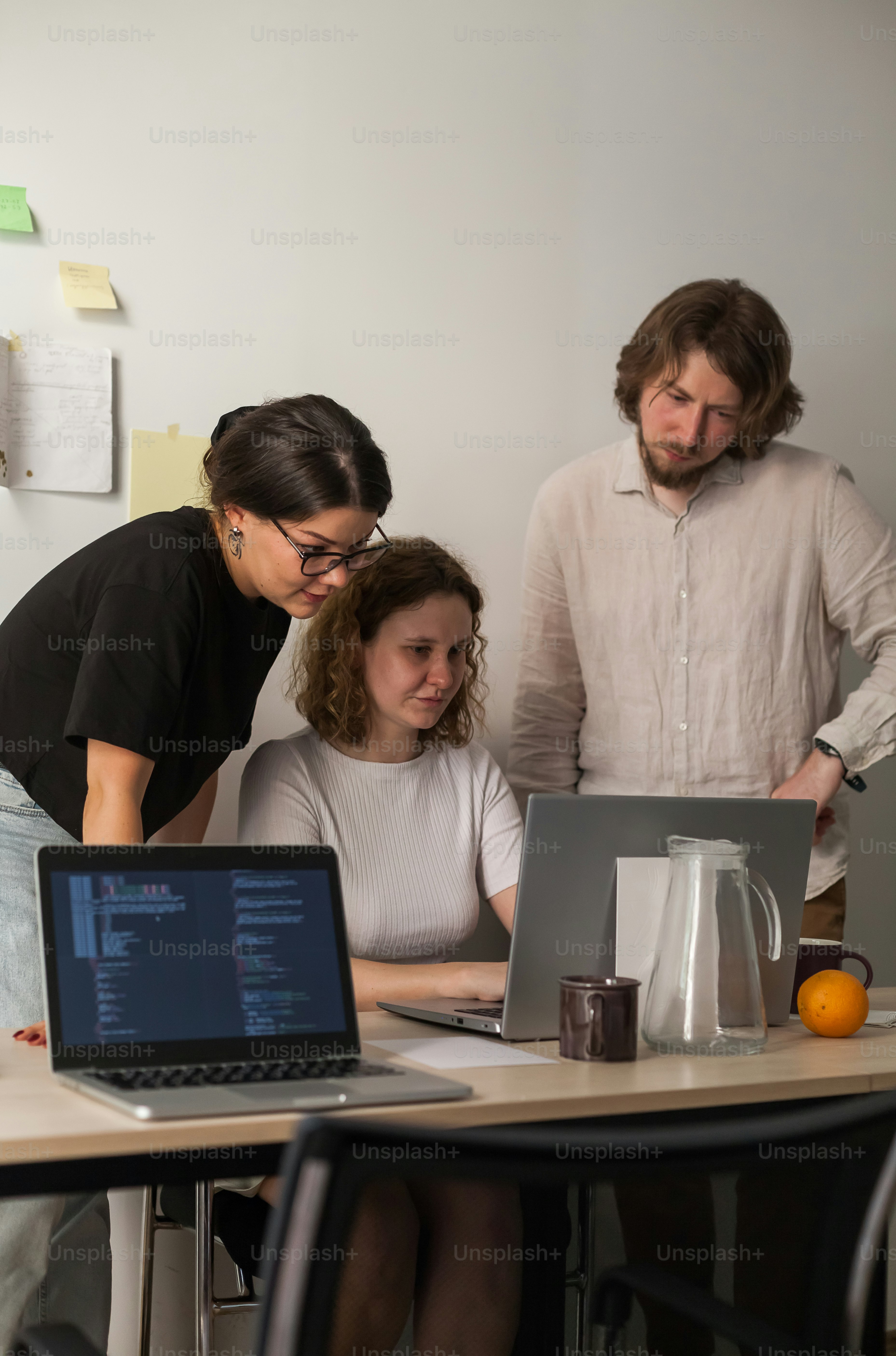 A group of people standing around a table with laptops photo ...