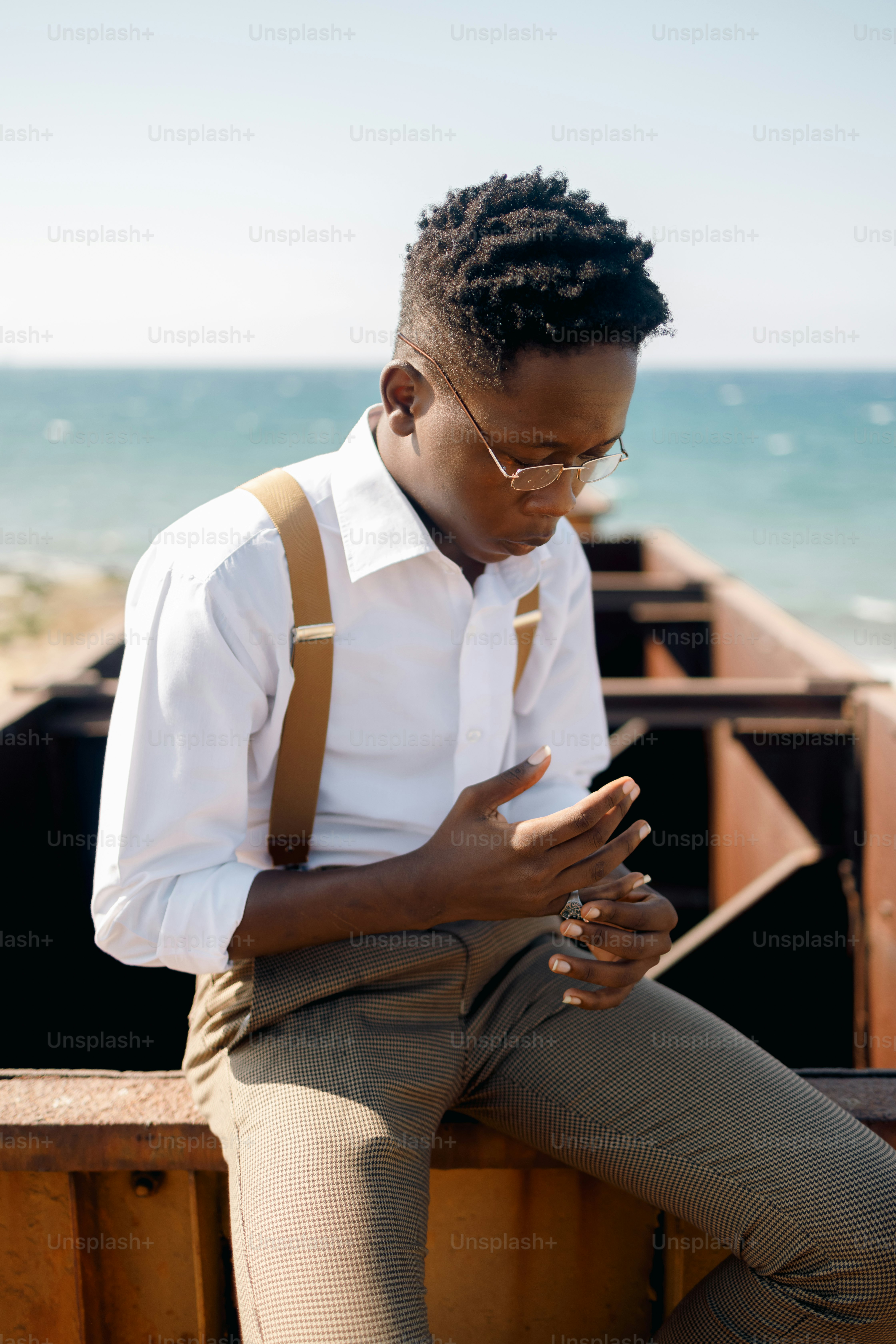 A man sitting on a rail looking at his cell phone photo – Lefke avrupa ...