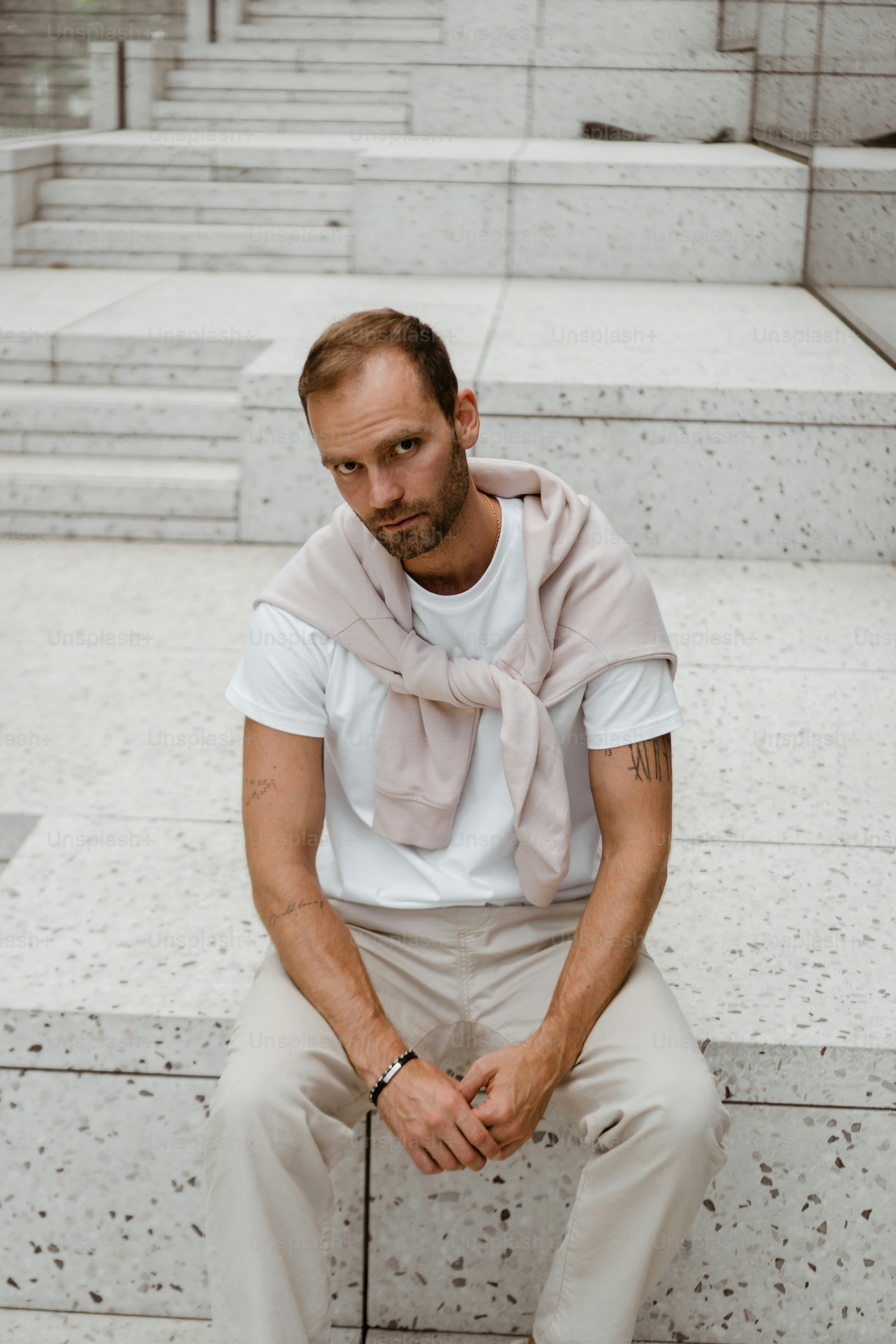A man sitting on steps with a scarf around his neck photo – Fashion ...